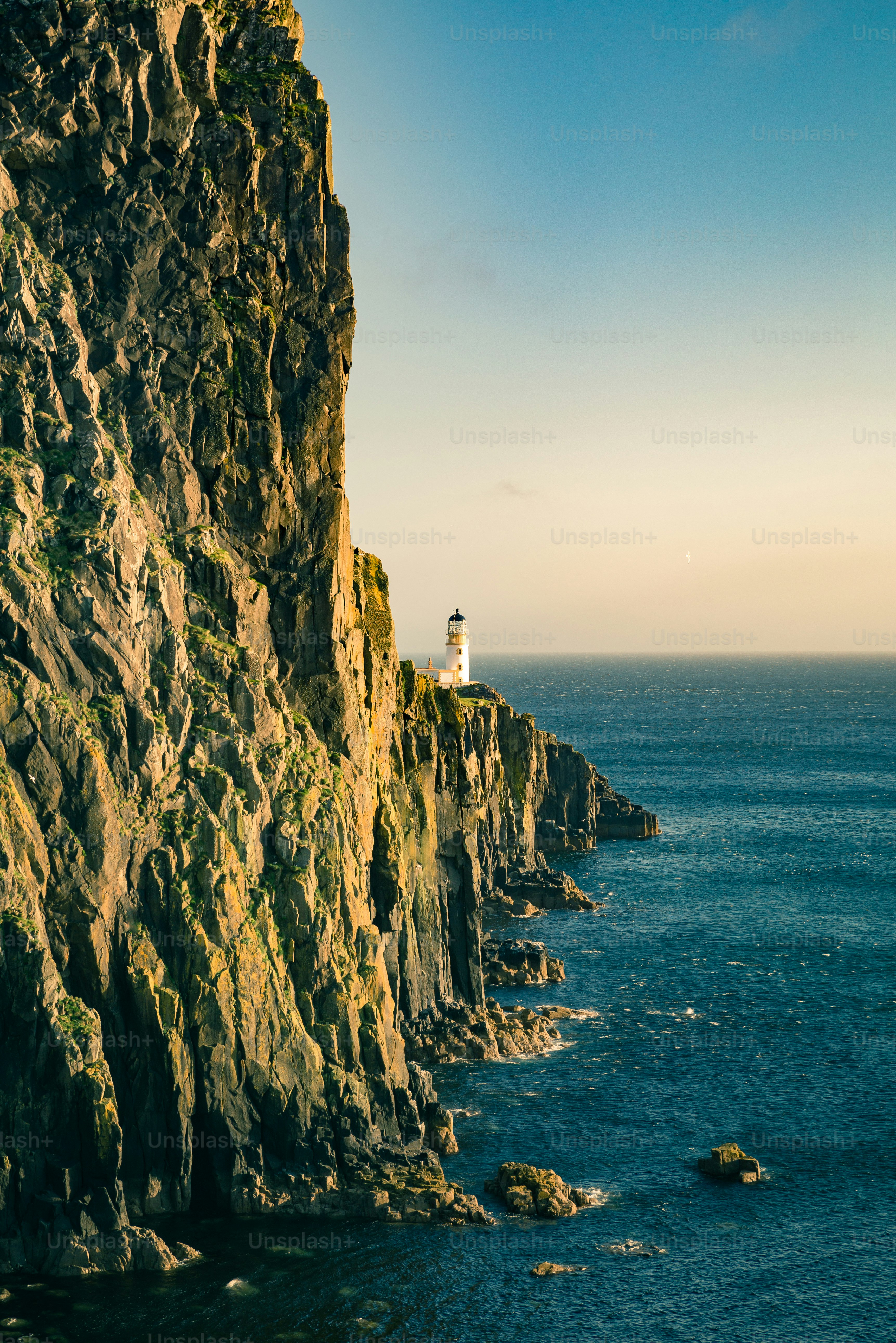 A lighthouse on a cliff overlooking the ocean photo – Neist point Image ...
