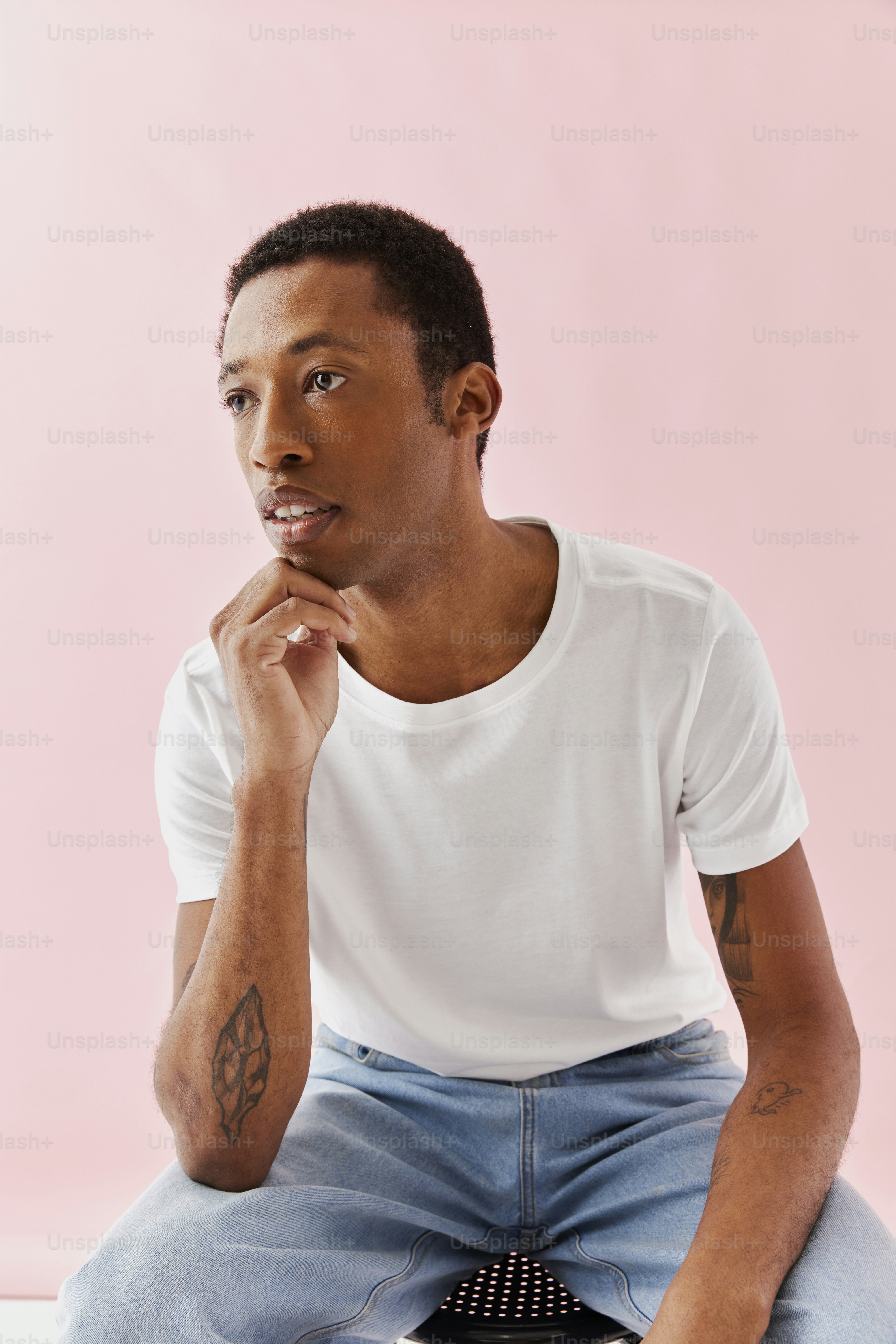 A man sitting on a stool with his hand on his chin photo – Mens fashion ...