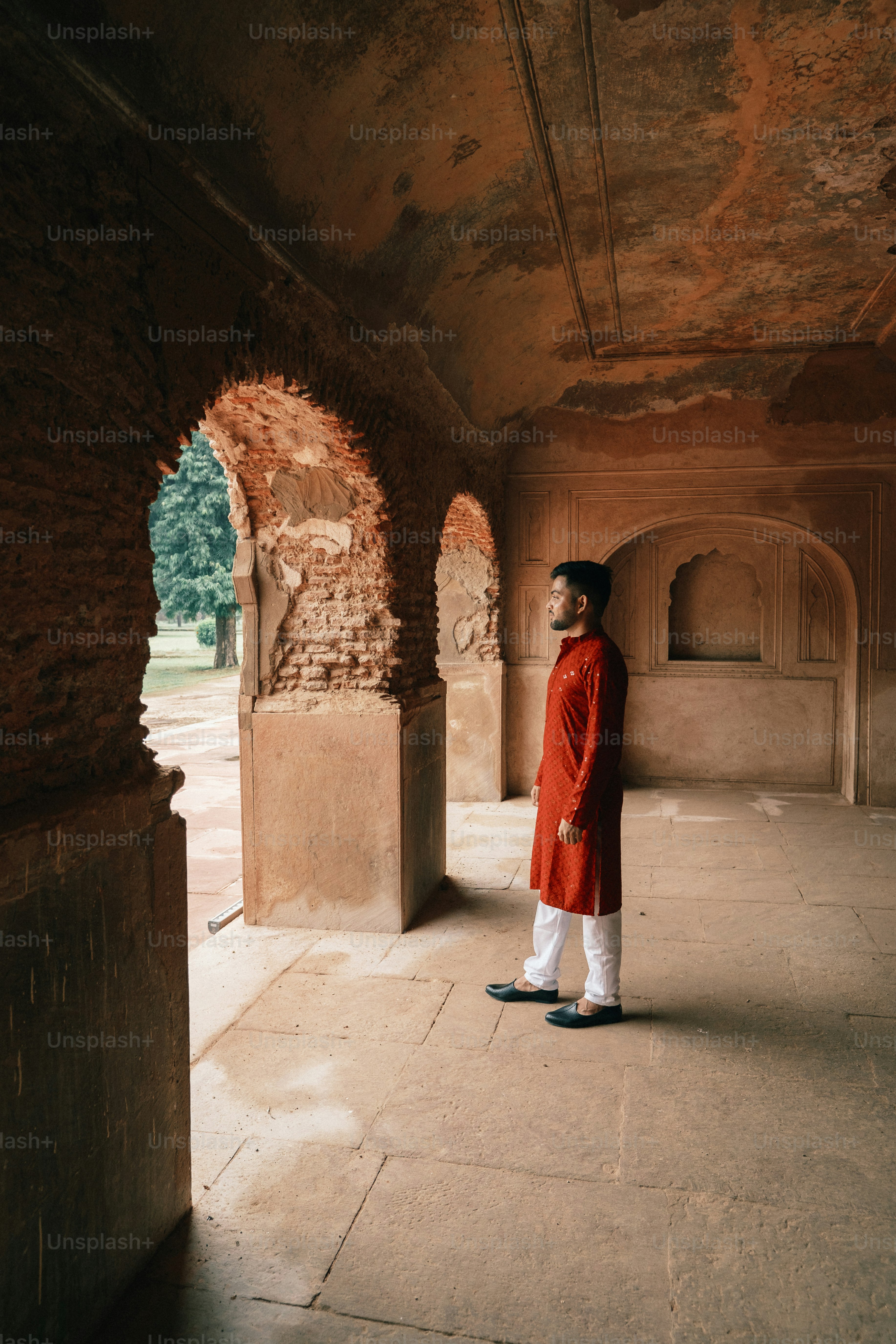 Un homme en tenue rouge debout dans une pièce photo – Masculin Photo ...