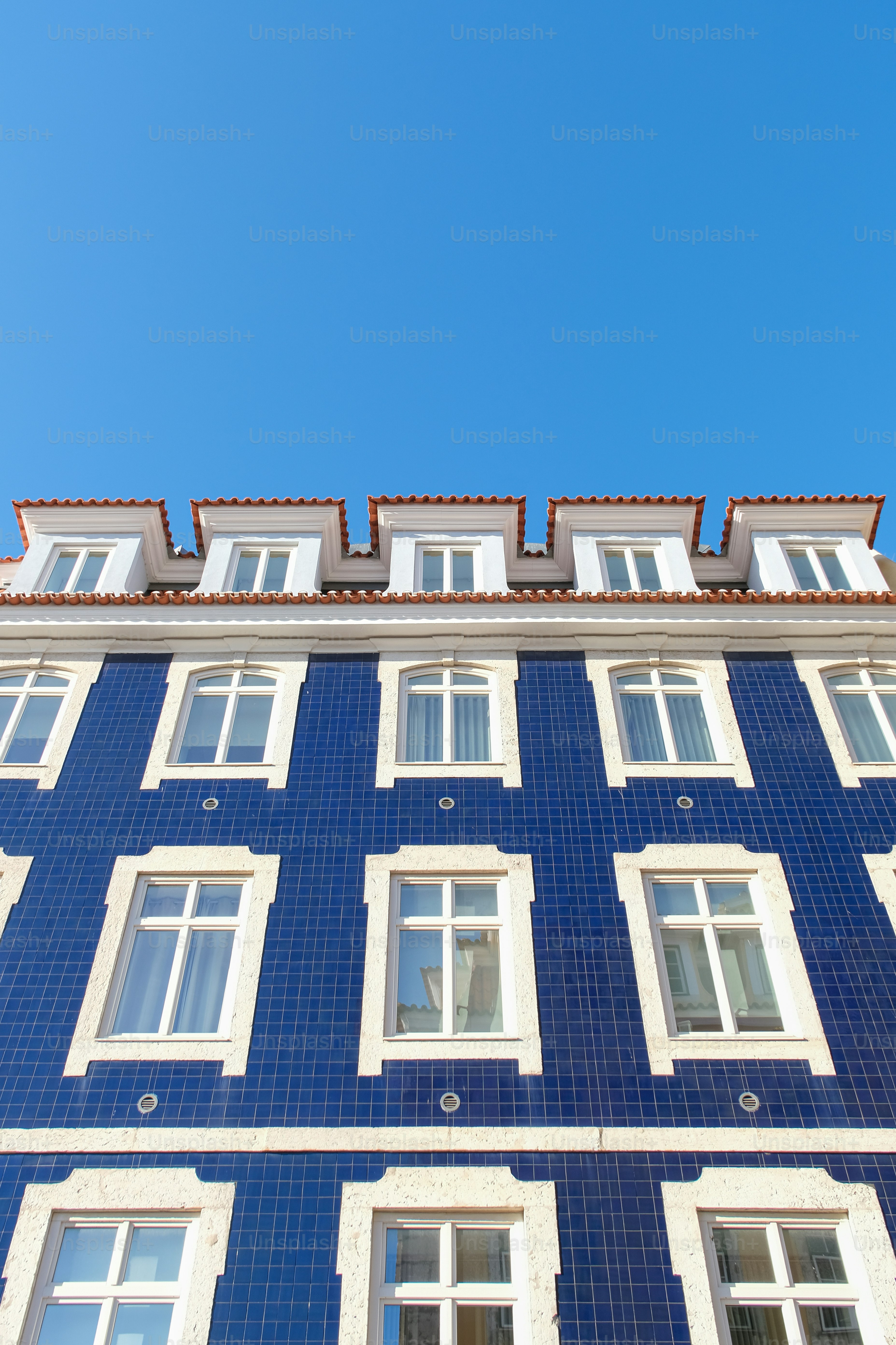 A blue and white building with windows and tiled roof photo – Blue ...