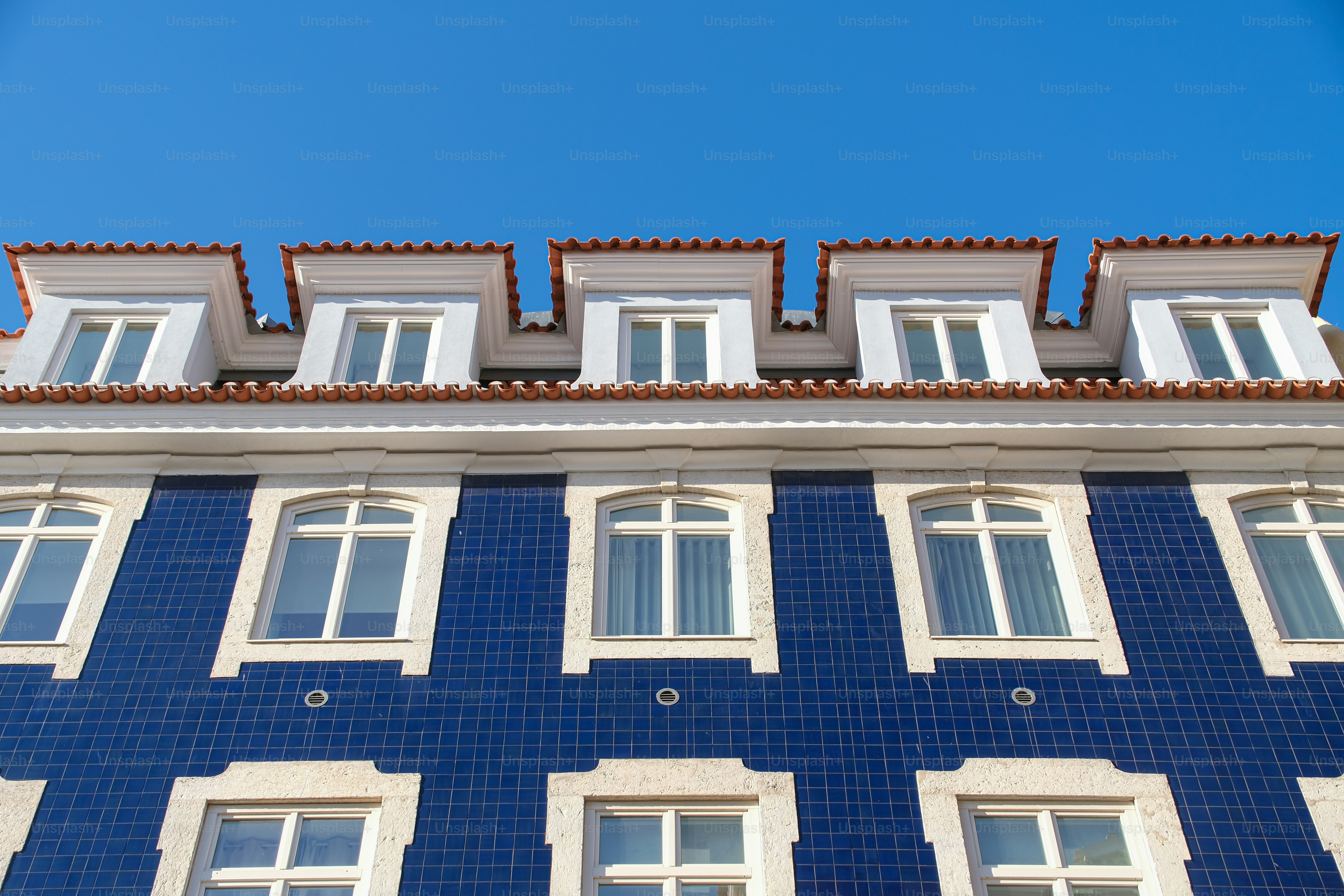 A blue and white building with windows and tiled roof photo – Europe ...