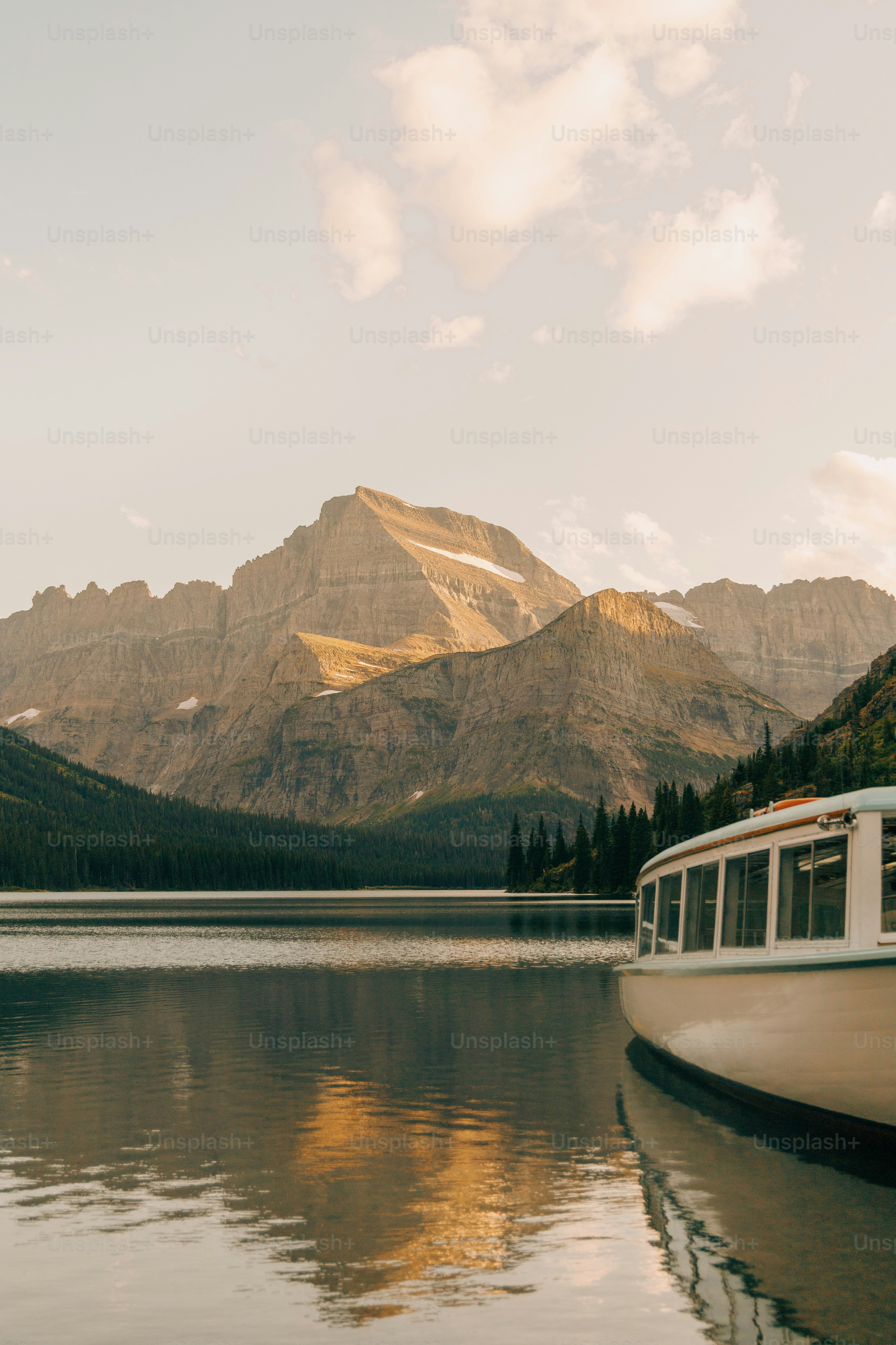 A boat floating on top of a lake surrounded by mountains photo ...