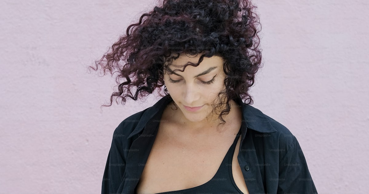 A Woman With Curly Hair Wearing Jeans And A Crop Top Photo Jeans Image On Unsplash