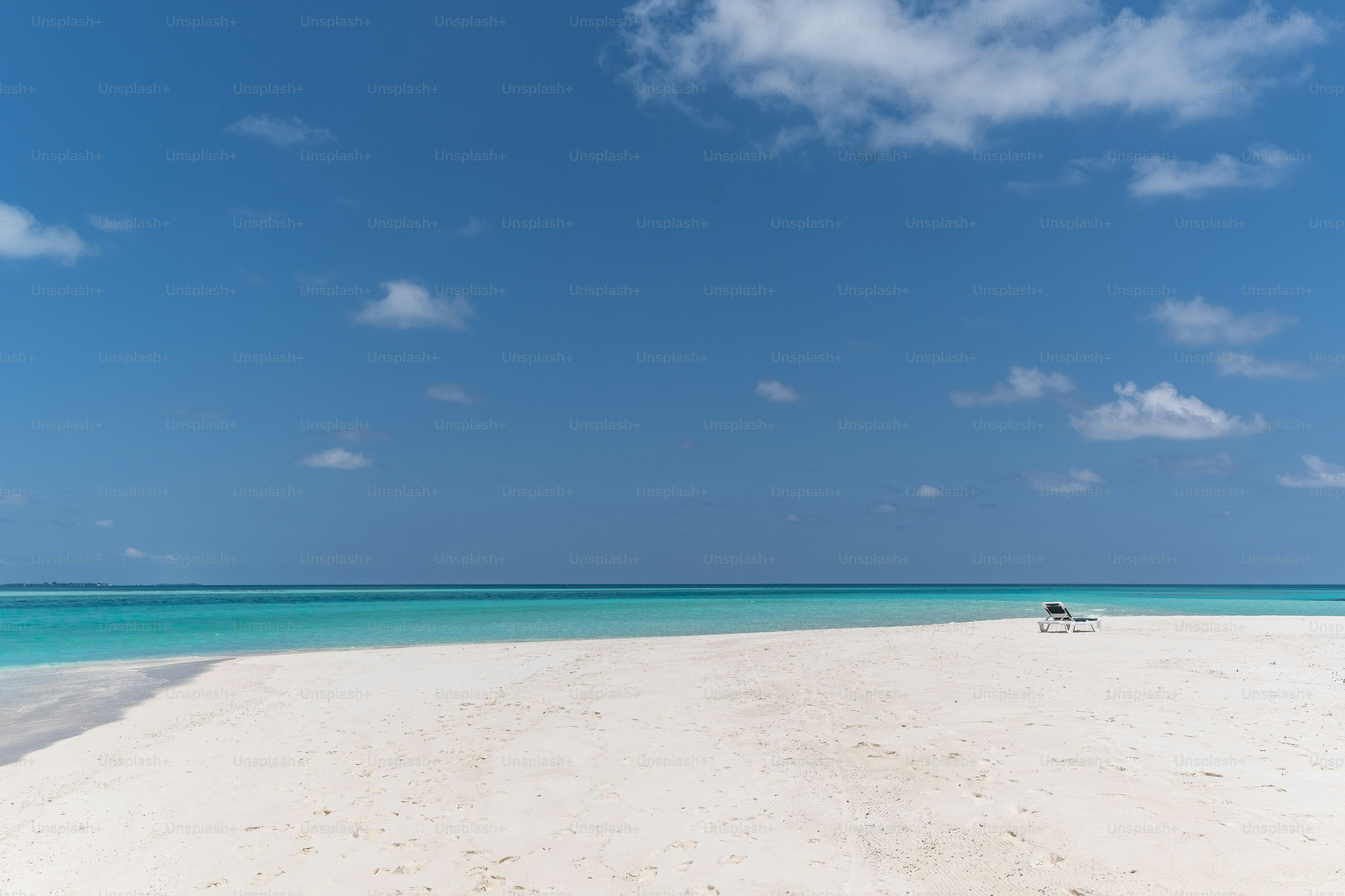 A sandy beach with clear blue water under a blue sky photo – Maldives ...