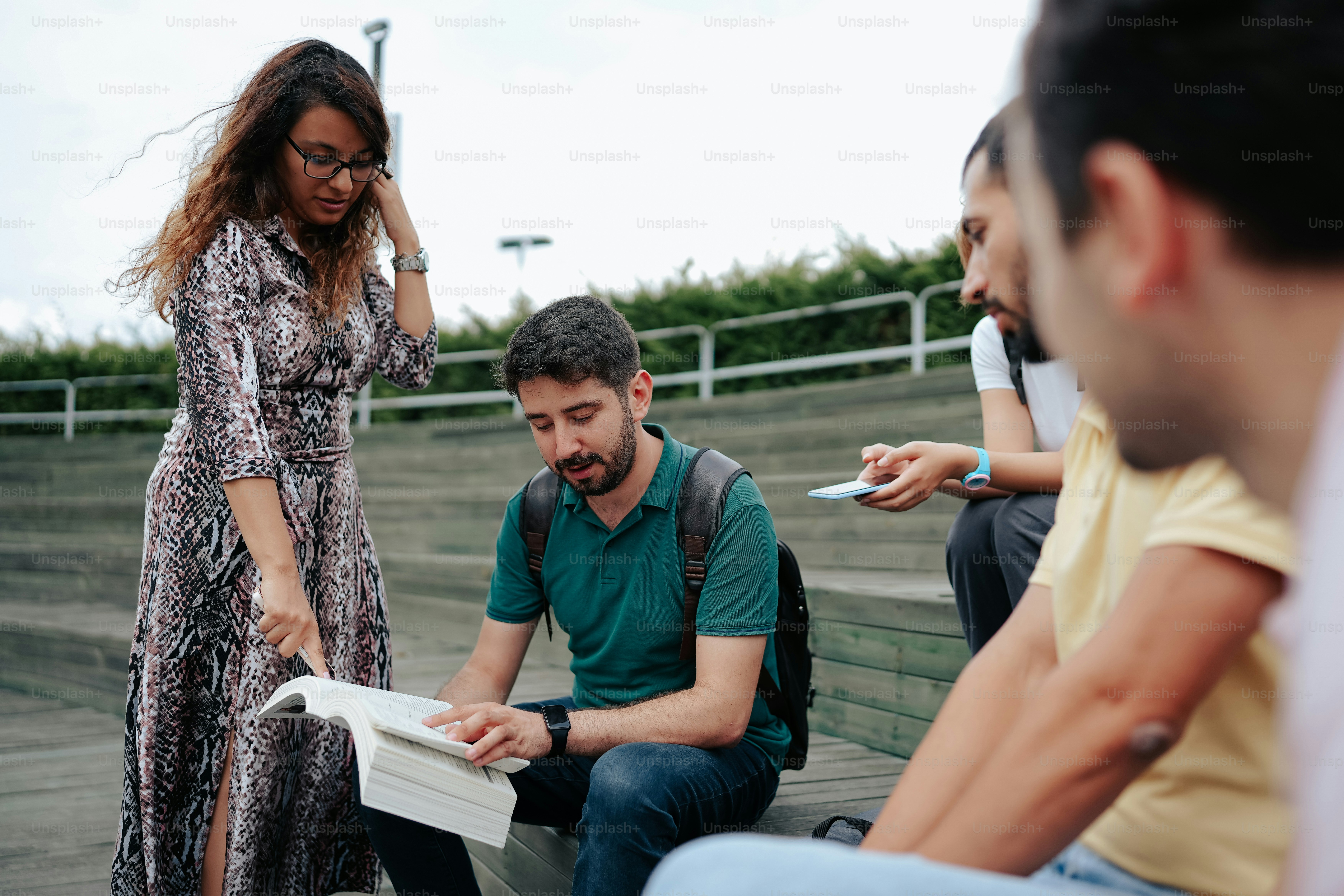 A group of people sitting on a bench next to each other photo – Campus ...