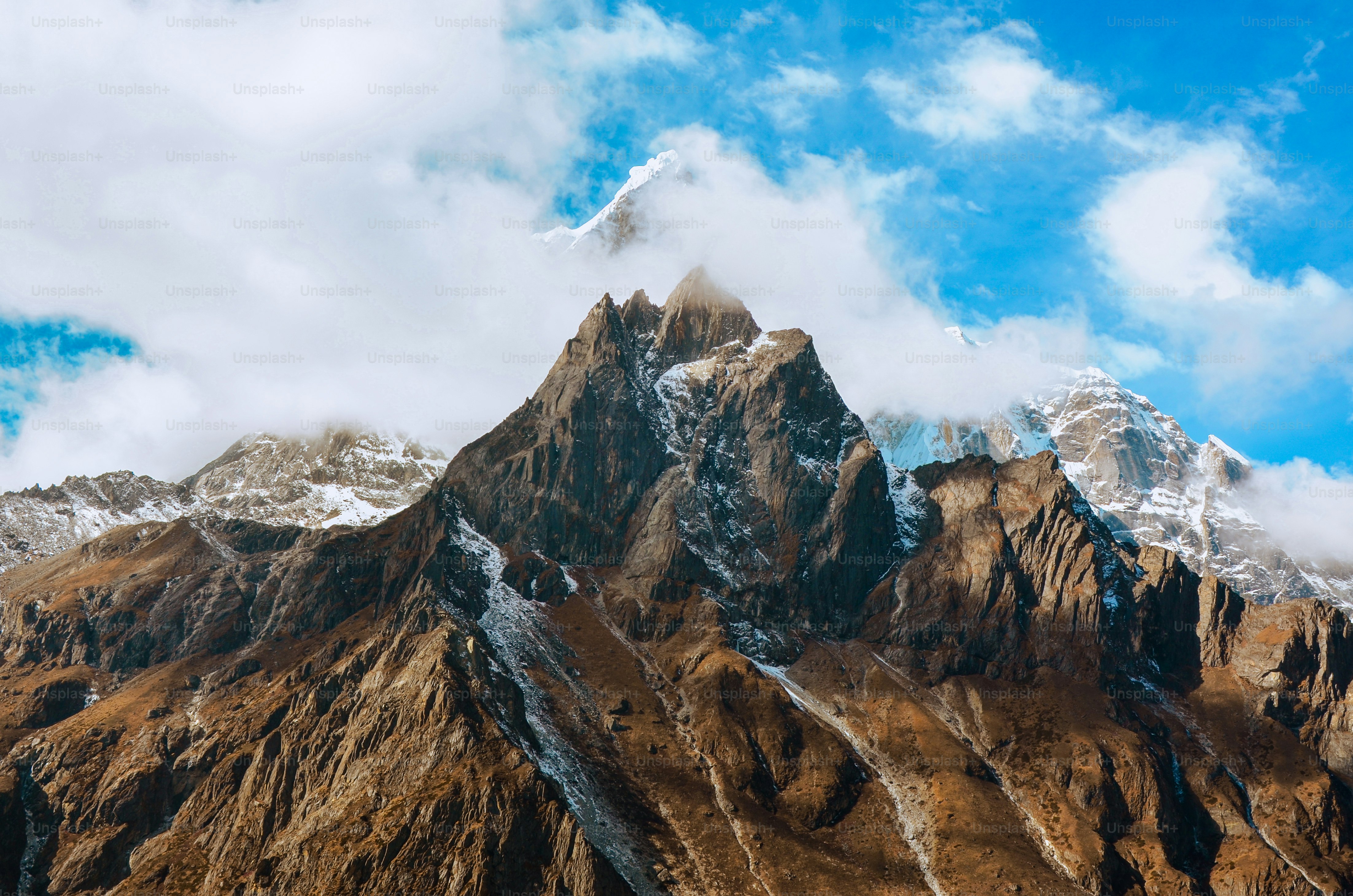 A very tall mountain covered in snow under a blue sky photo – Himalayas ...