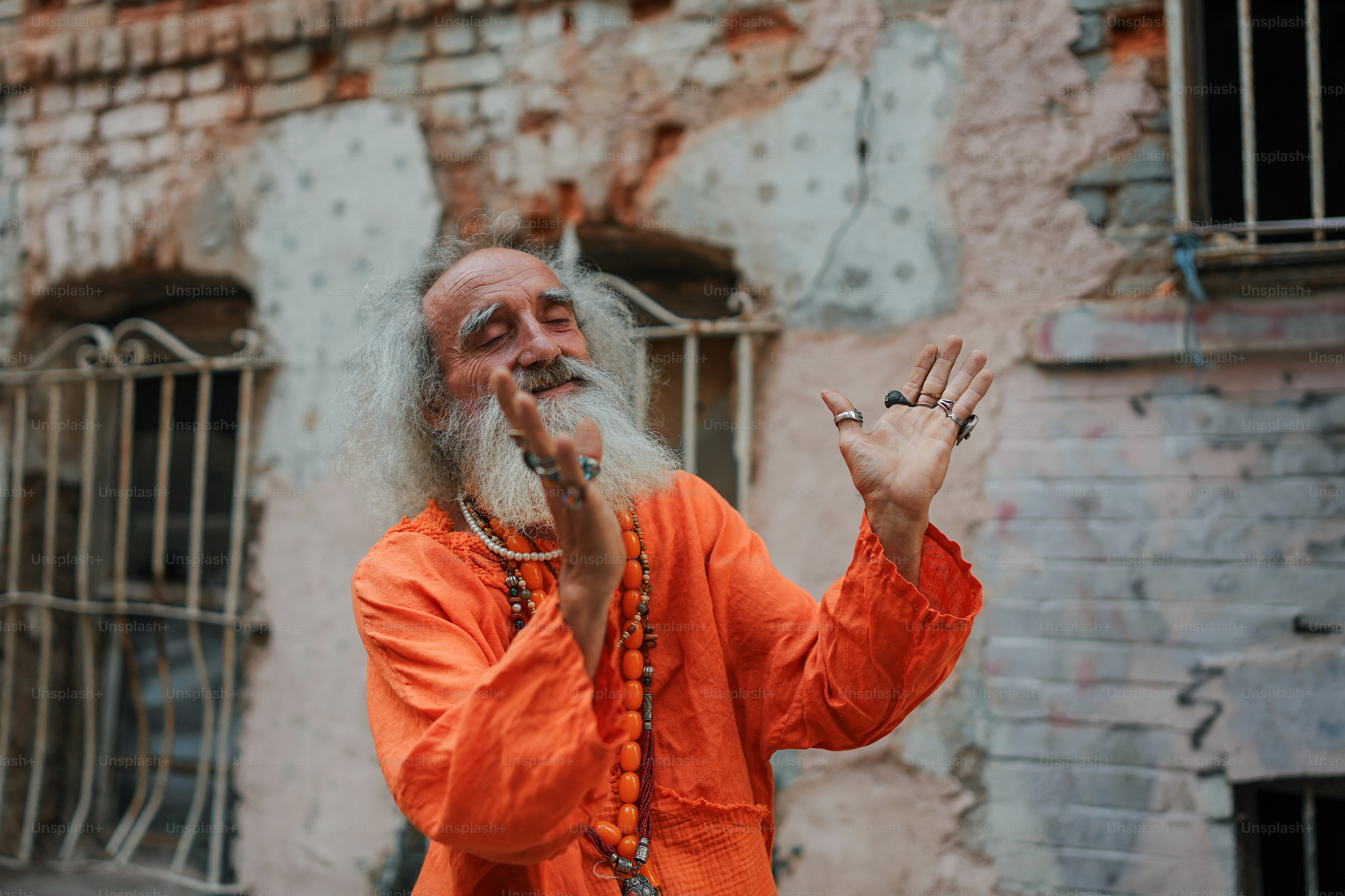 A man in an orange outfit holding beads photo – Old man Image on Unsplash