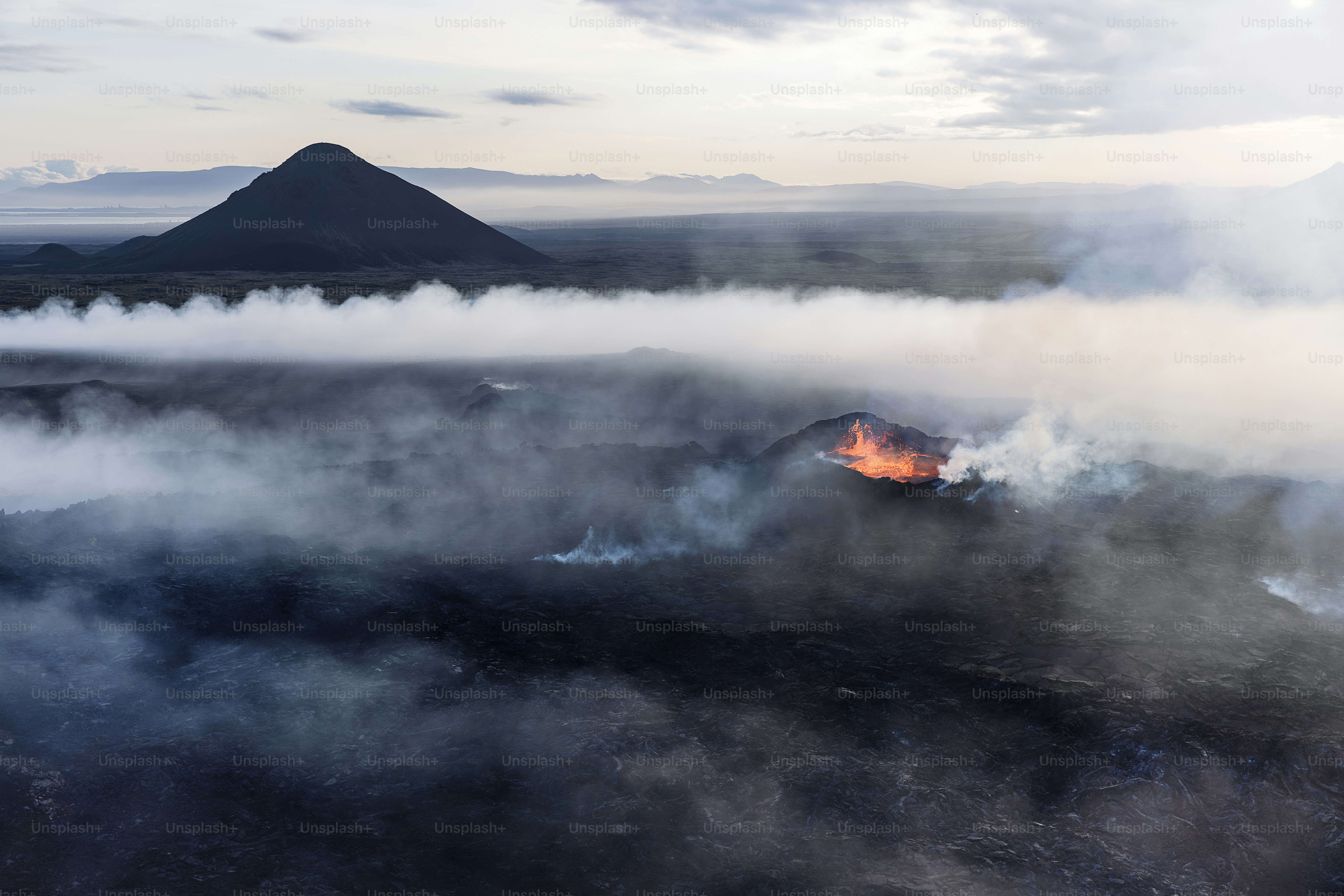 A volcano spewing out lava in the middle of a field photo – Lava Image ...