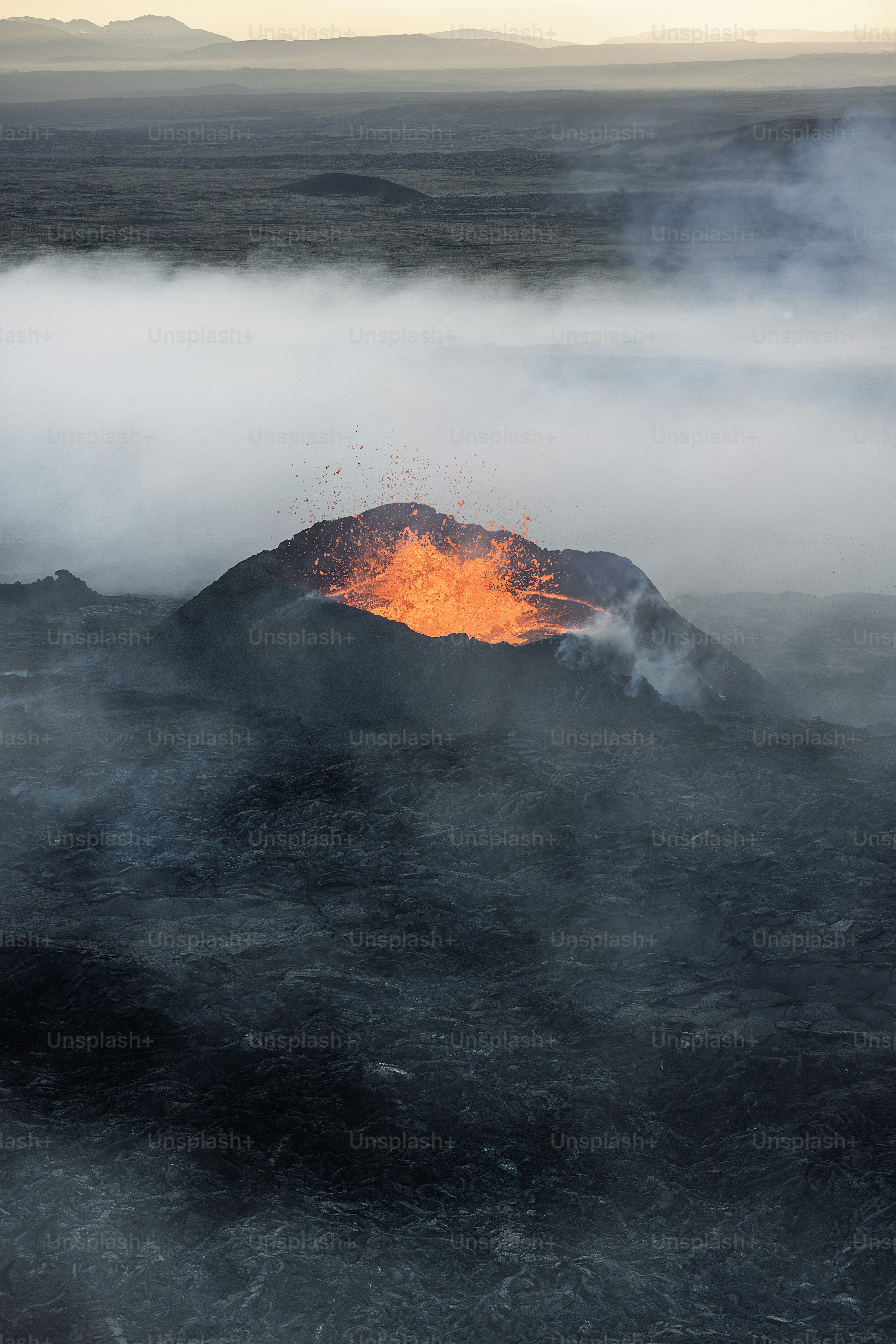 A small volcano with a lot of smoke coming out of it photo ...