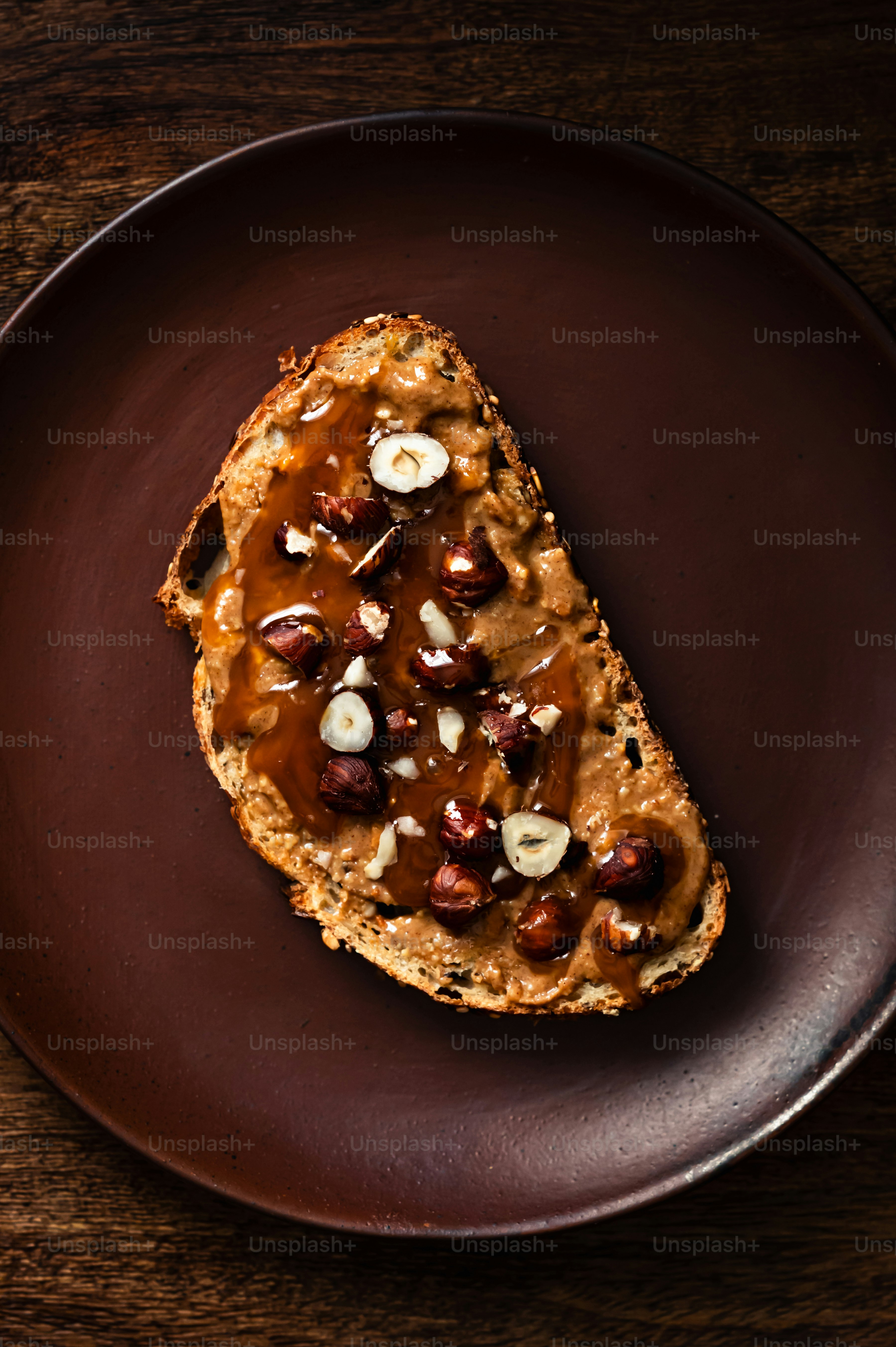A piece of bread with nuts and cheese on a plate photo – Monochromatic ...