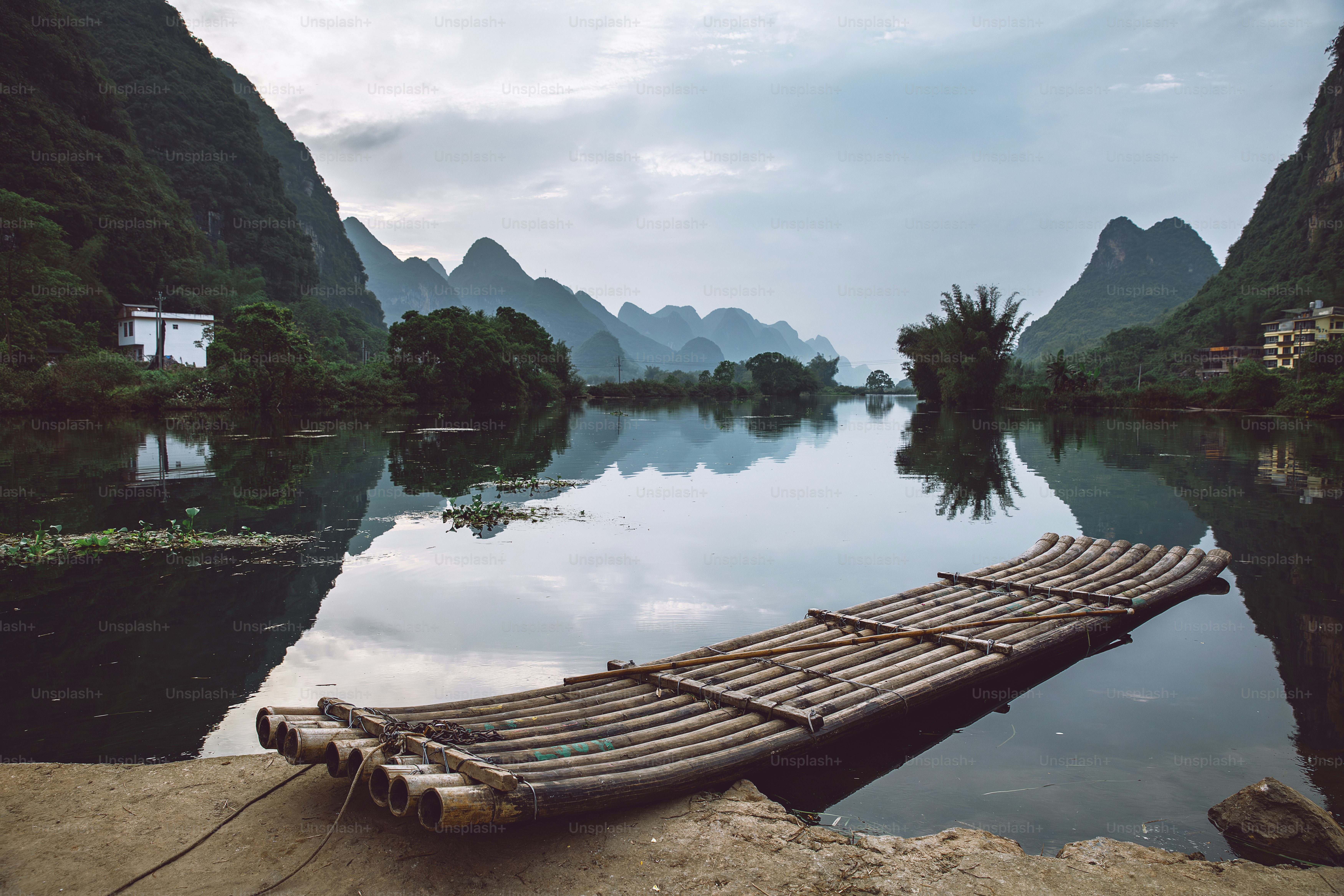 A long wooden raft sitting on top of a river photo – River Image on ...
