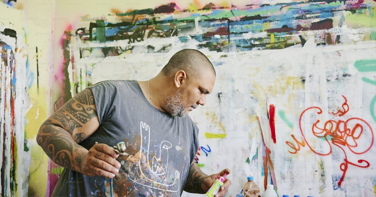 Un Homme Debout Devant Un Mur Couvert De Beaucoup De Peinture Photo