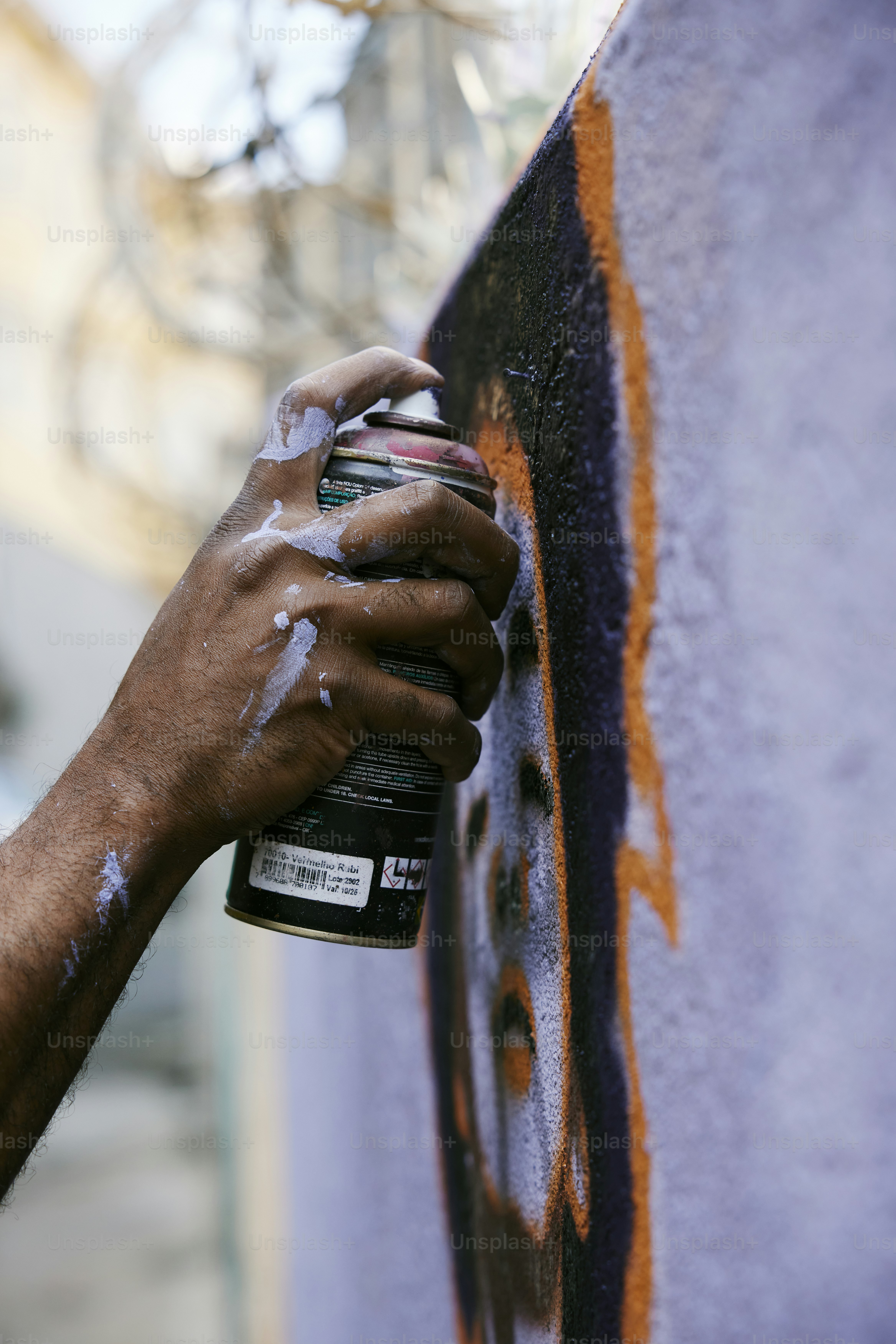 A person spray painting a wall with orange and black paint photo ...