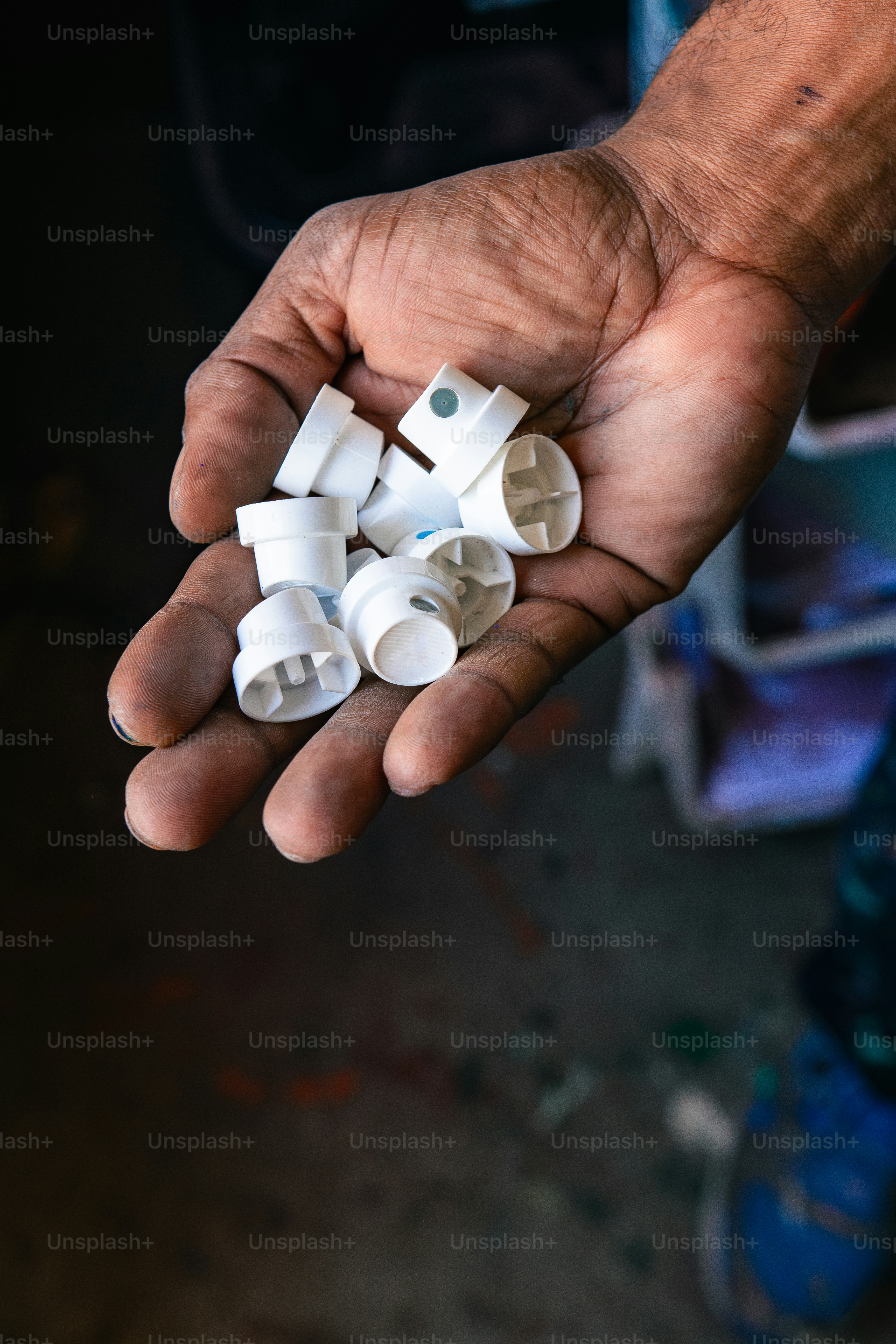 A person holding a handful of white plastic objects photo – Mural Image ...