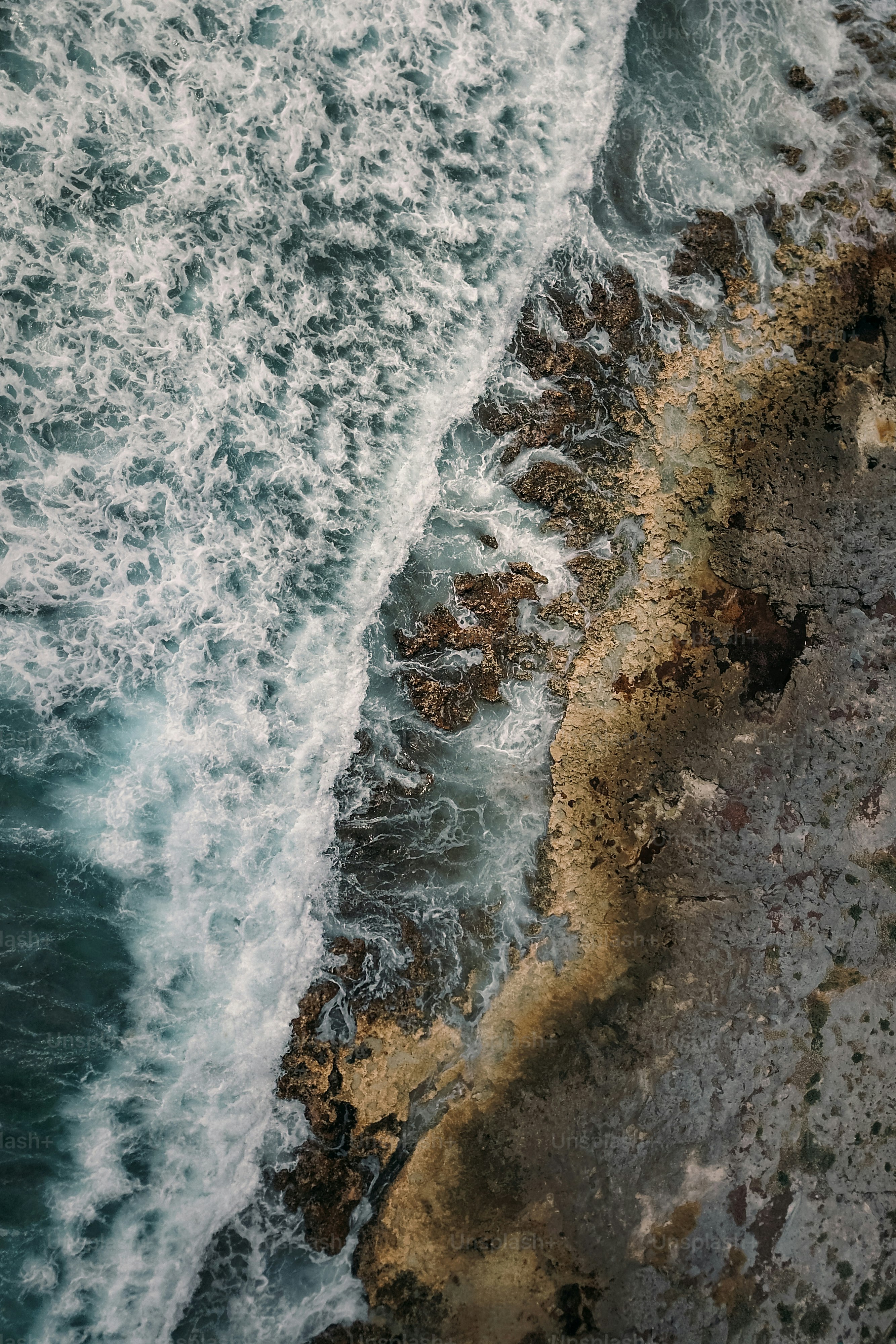 An aerial view of the ocean with waves crashing on the shore photo ...