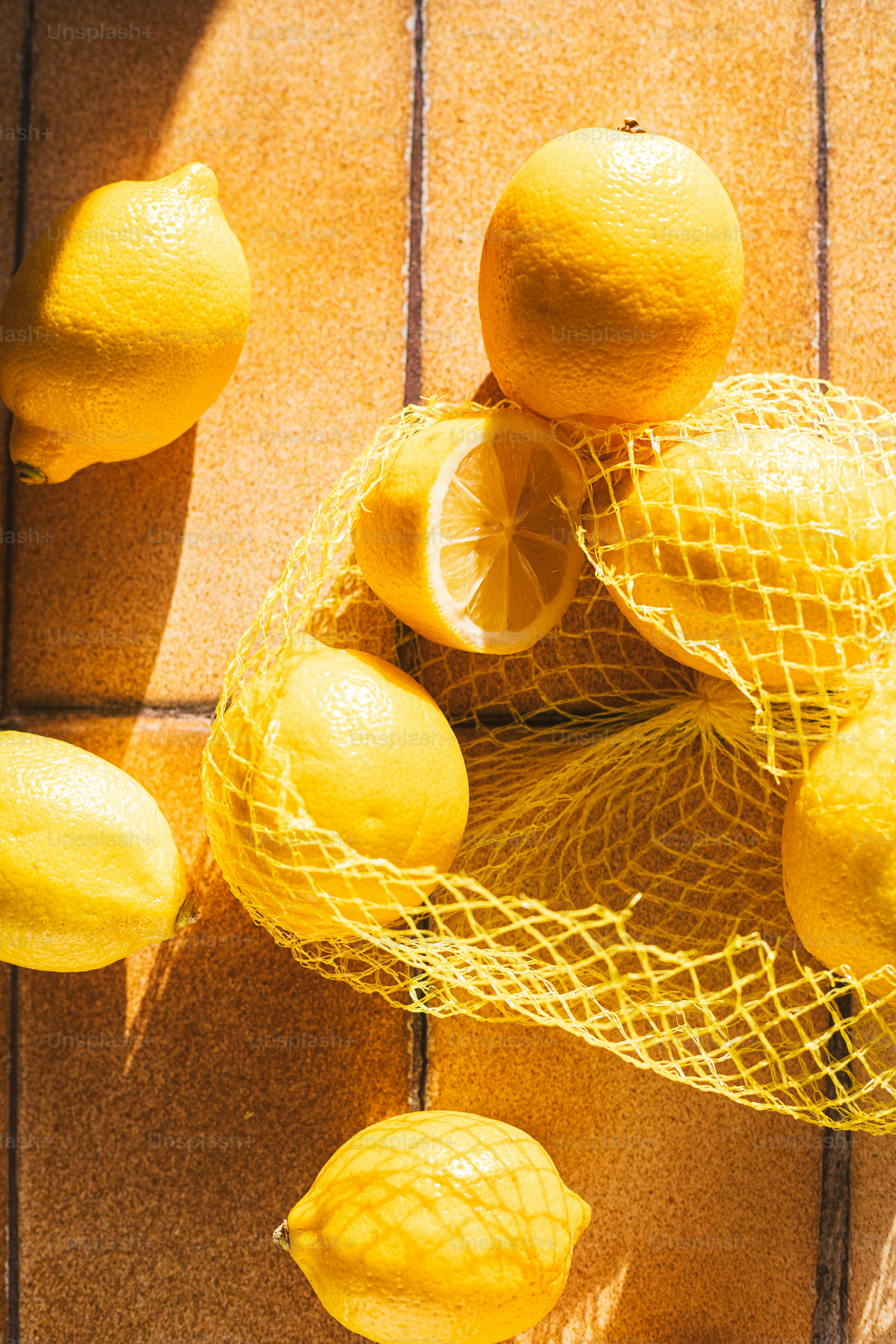 A mesh bag filled with lemons on top of a wooden floor photo – Lemons ...