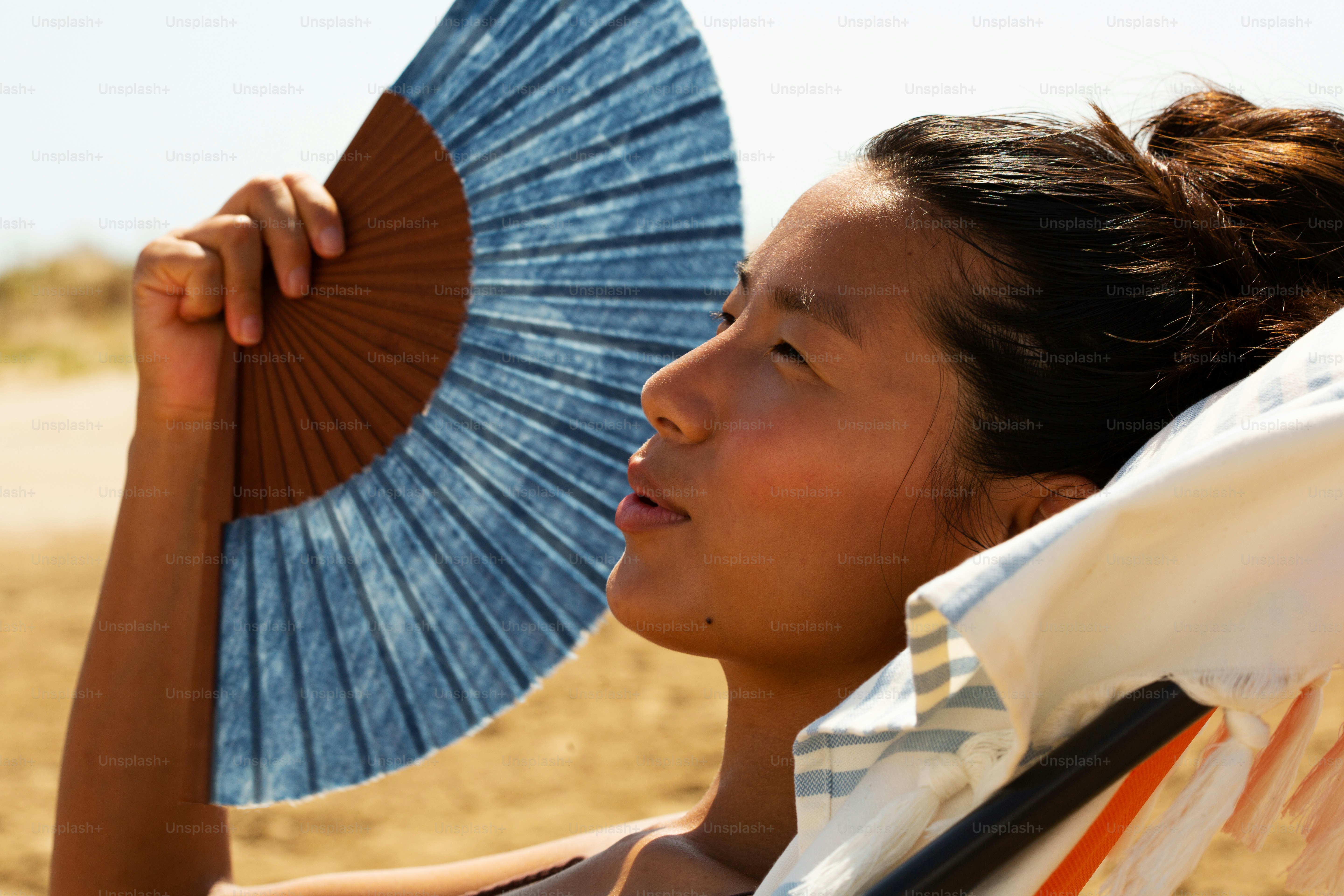 Foto Una mujer sentada en una silla de playa sosteniendo una sombrilla ...