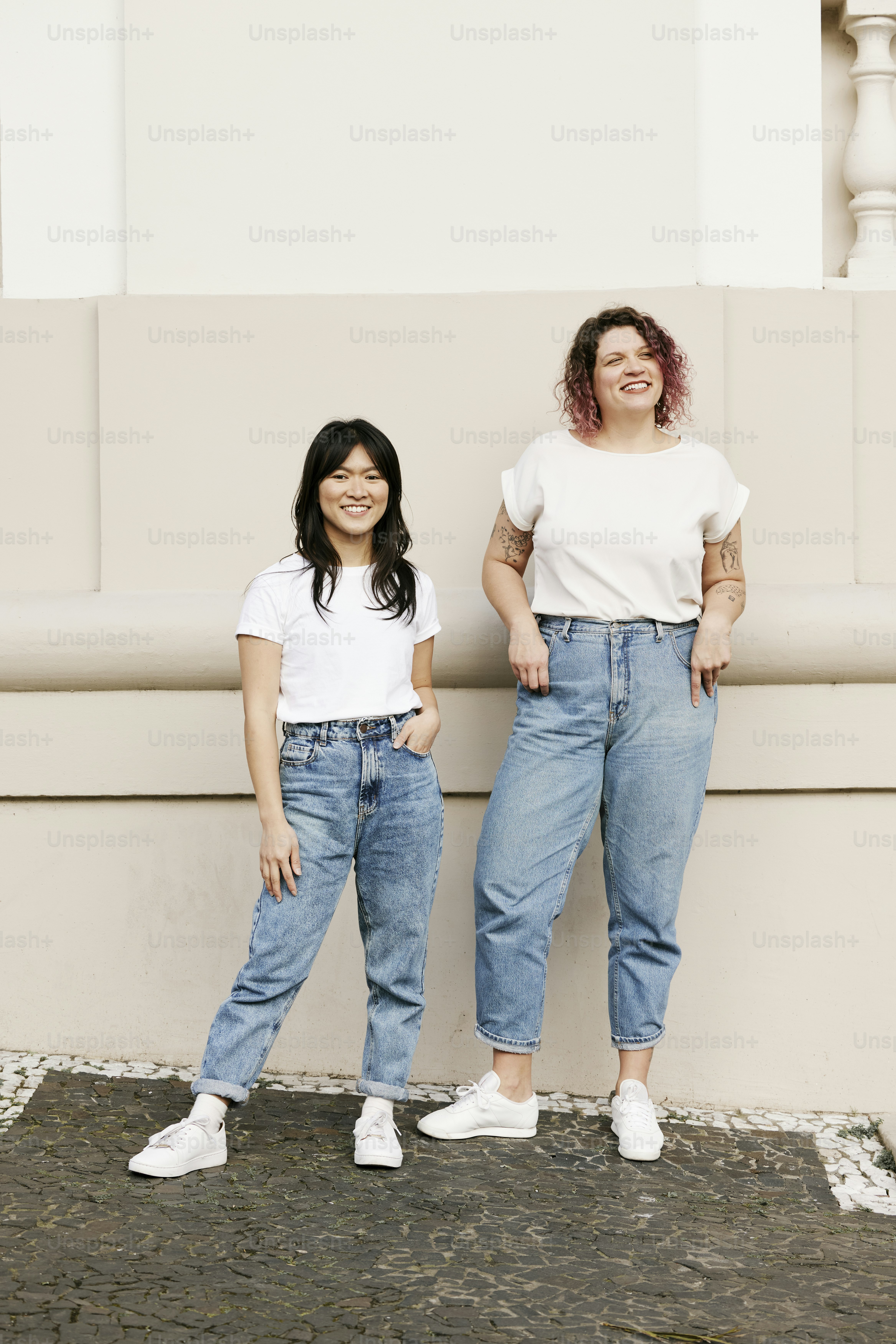 Two women standing next to each other in front of a building photo ...
