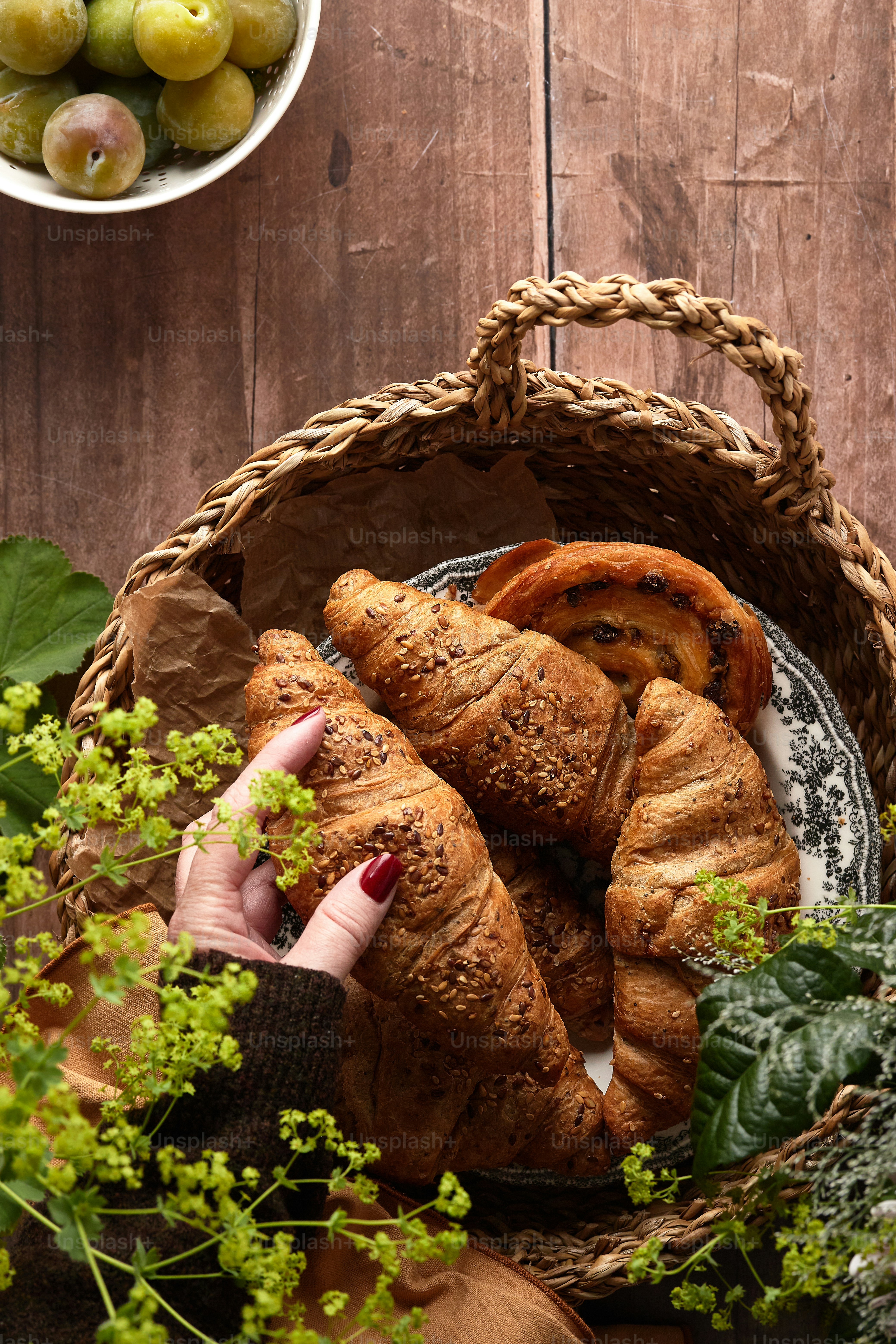 A basket filled with croissants next to a bowl of fruit photo ...