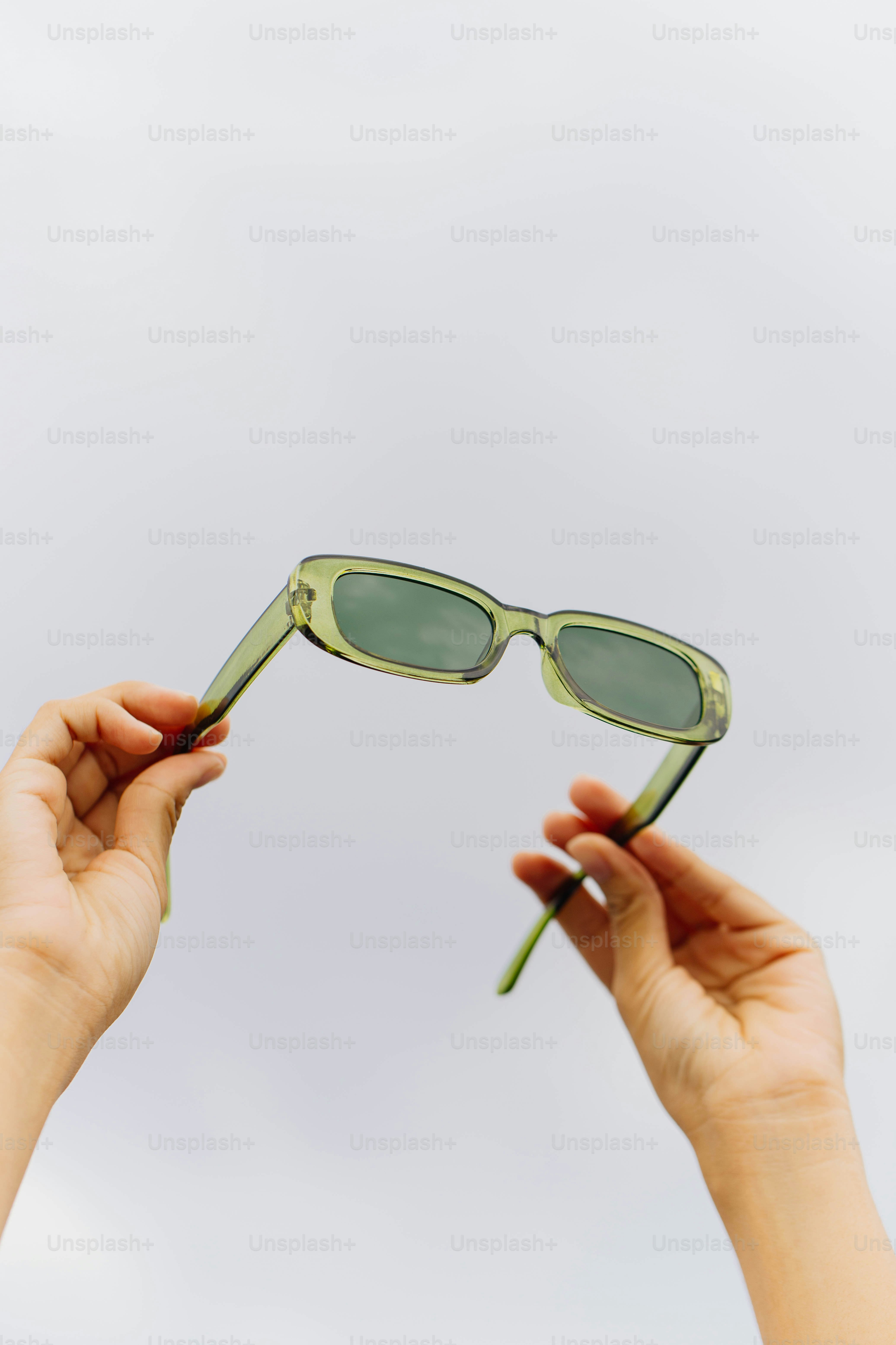 A pair of hands holding a pair of green sunglasses photo – Green Image ...