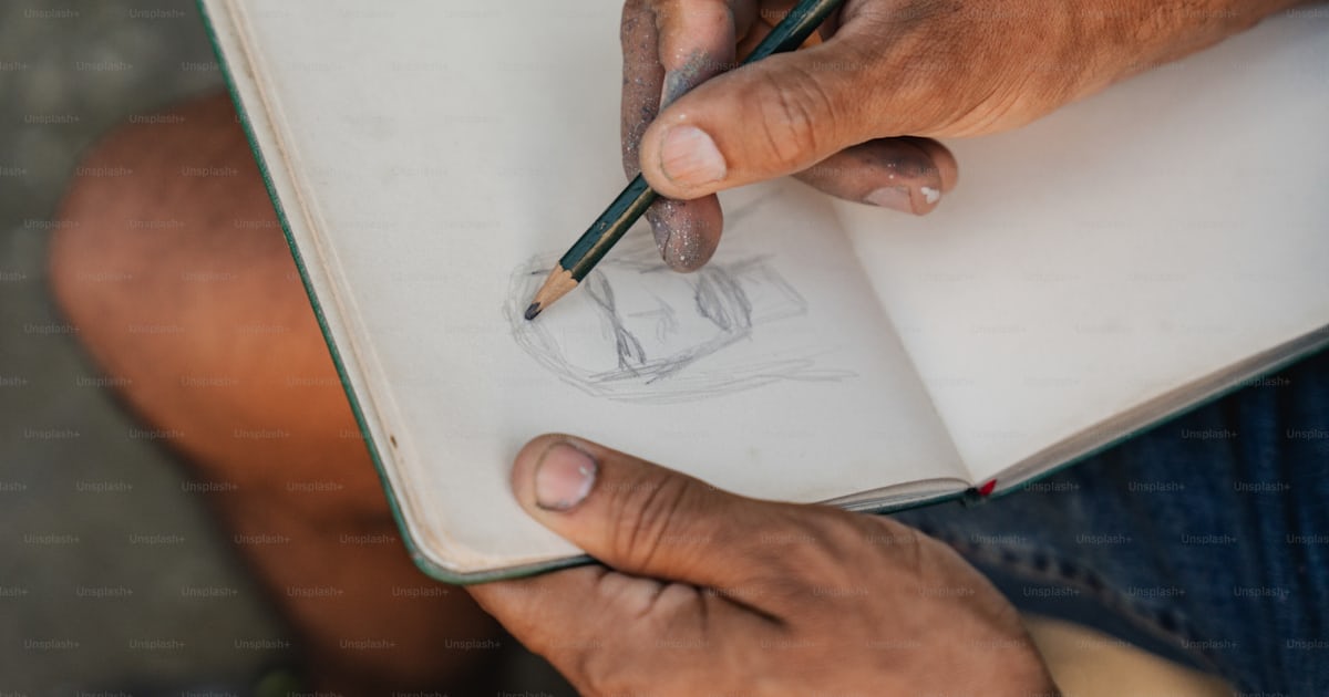 Une Personne Tenant Un Crayon Et Dessinant Sur Un Livre Photo Dessin