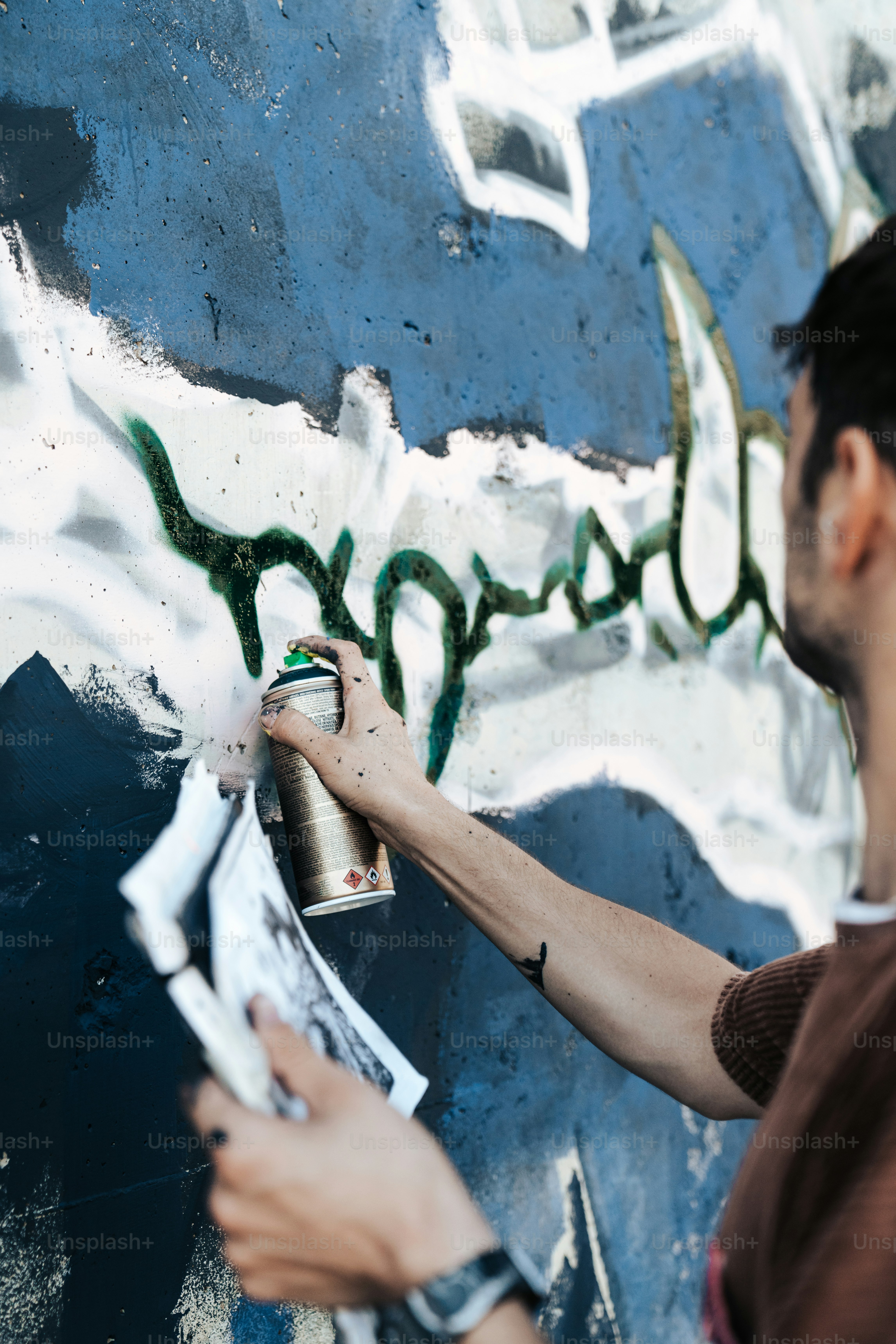 A man spray painting a wall with graffiti photo – Street art Image on ...