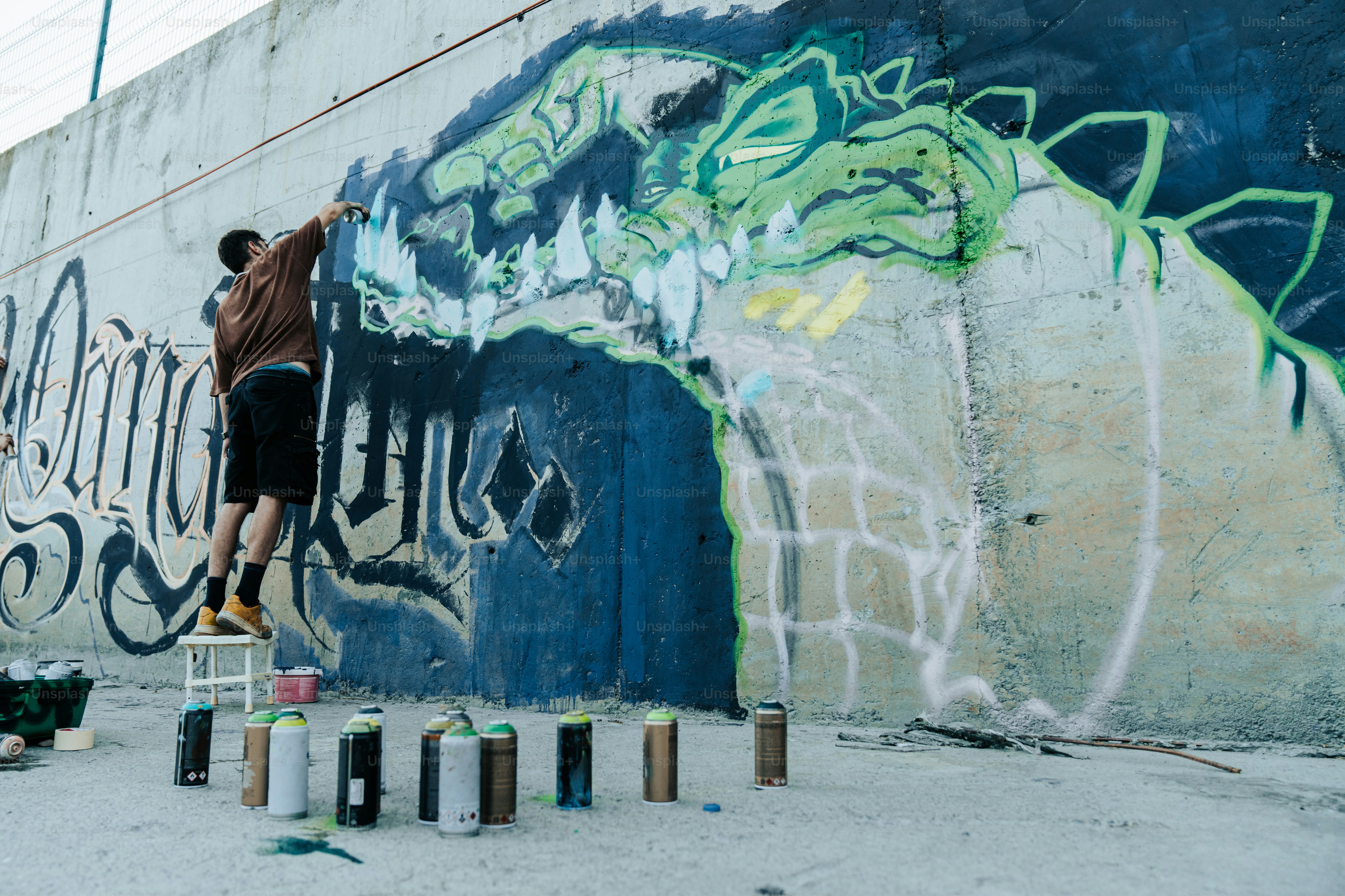 A man painting a wall with spray paint photo – Mural Image on Unsplash