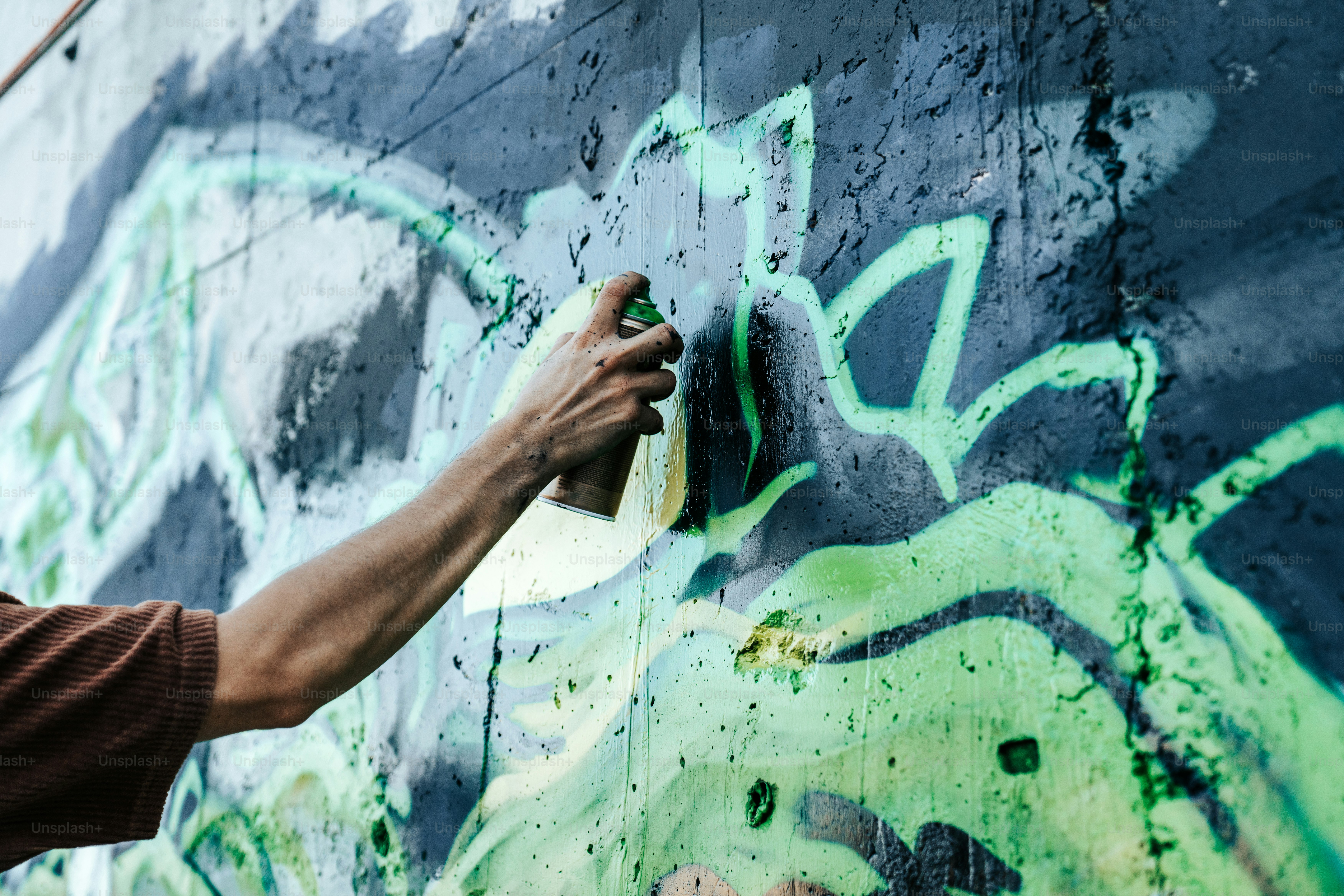 A man spray painting a wall with graffiti photo – Street art Image on ...
