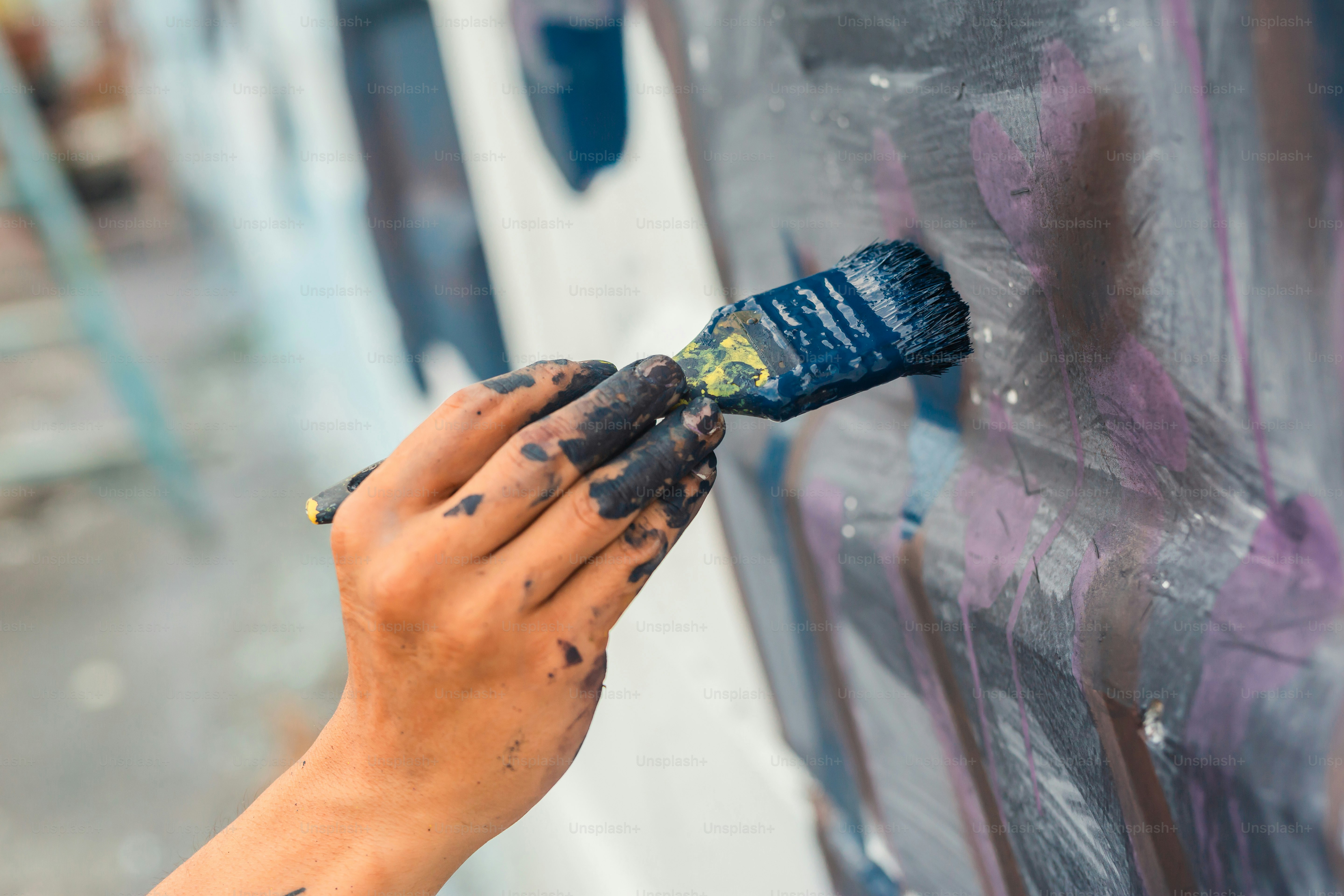 A person painting a wall with blue paint photo – Street art Image on ...