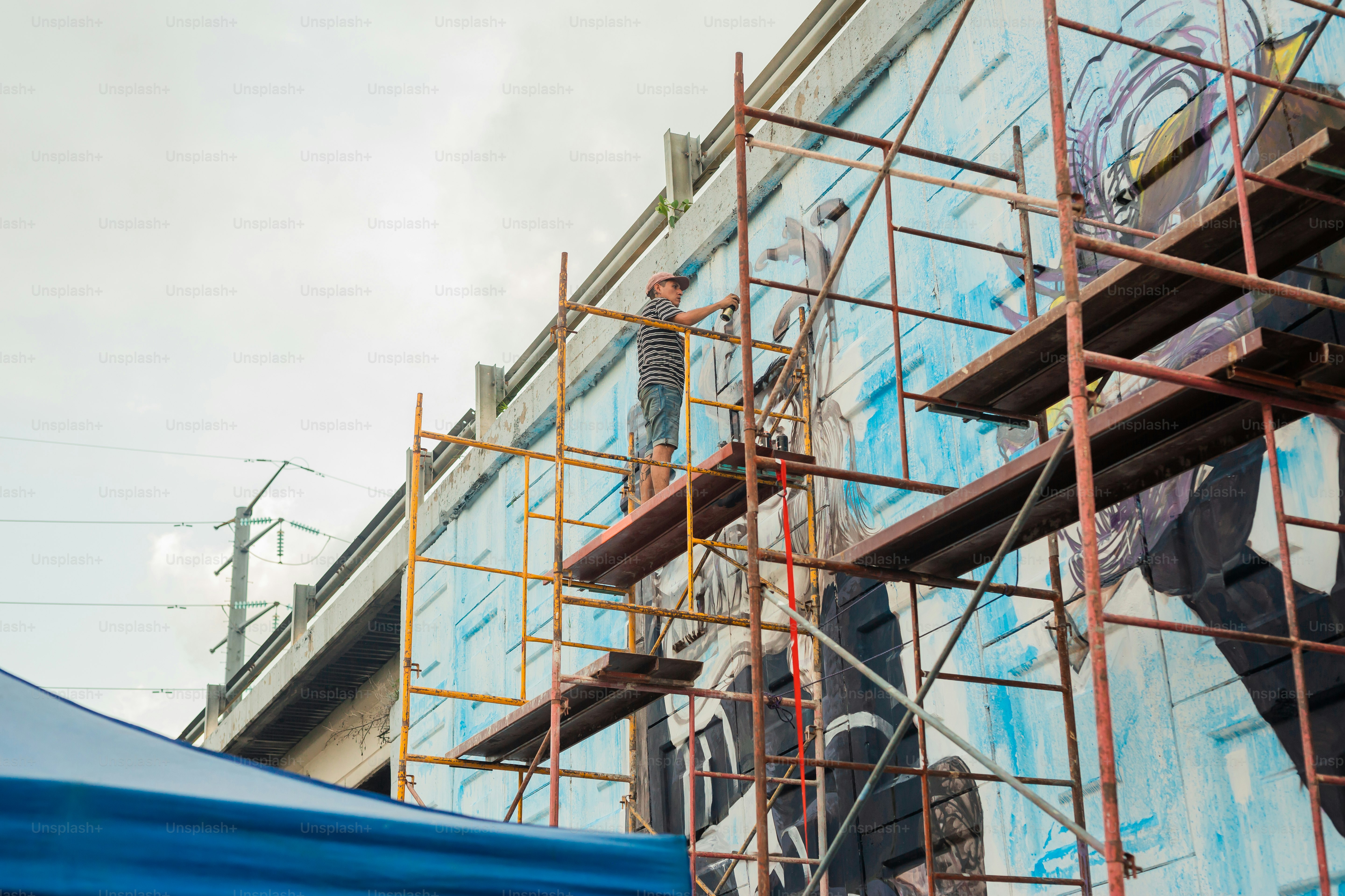 A building with scaffolding and a blue tarp photo – Street art Image on ...