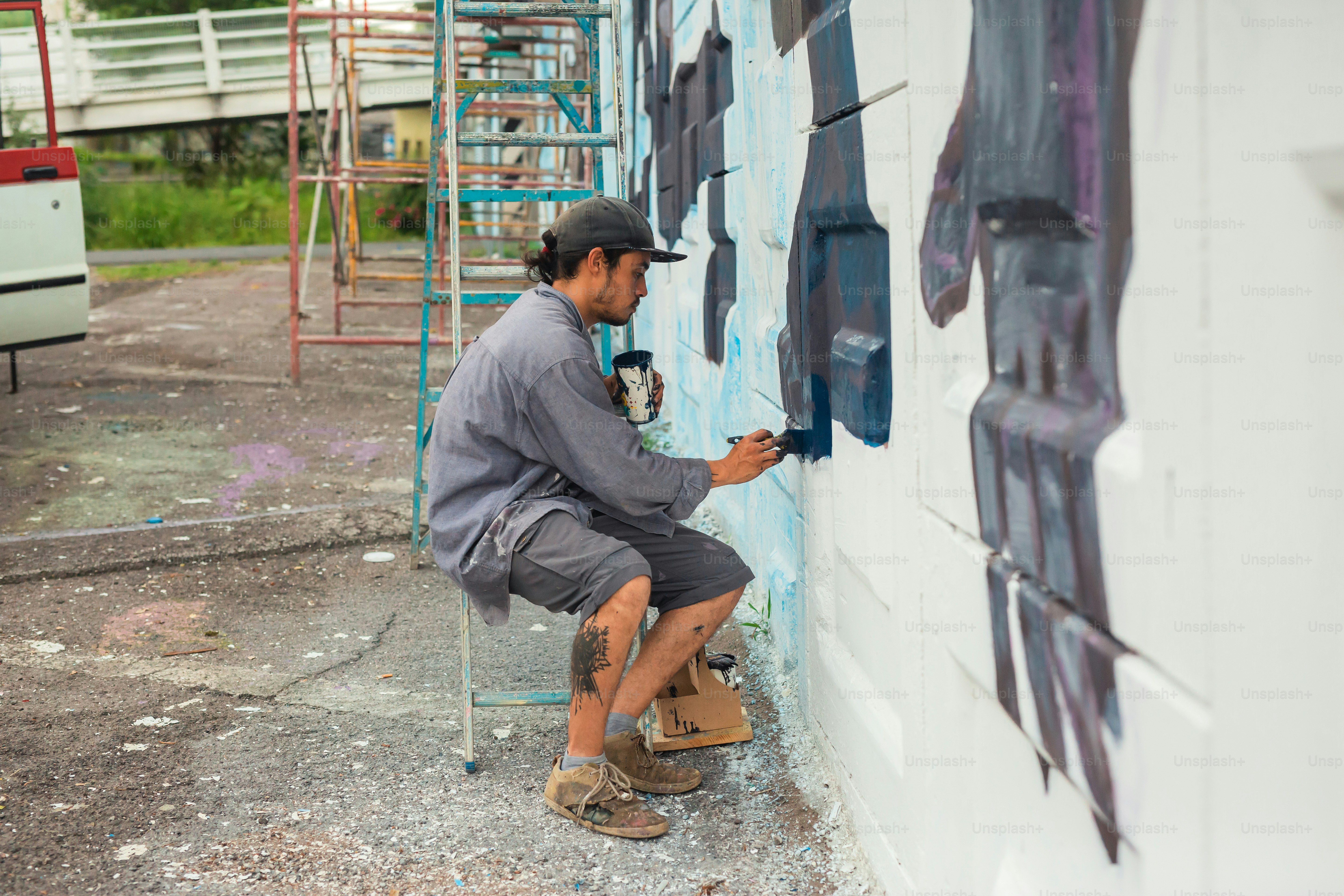 A man painting a wall with blue paint photo – Mural Image on Unsplash