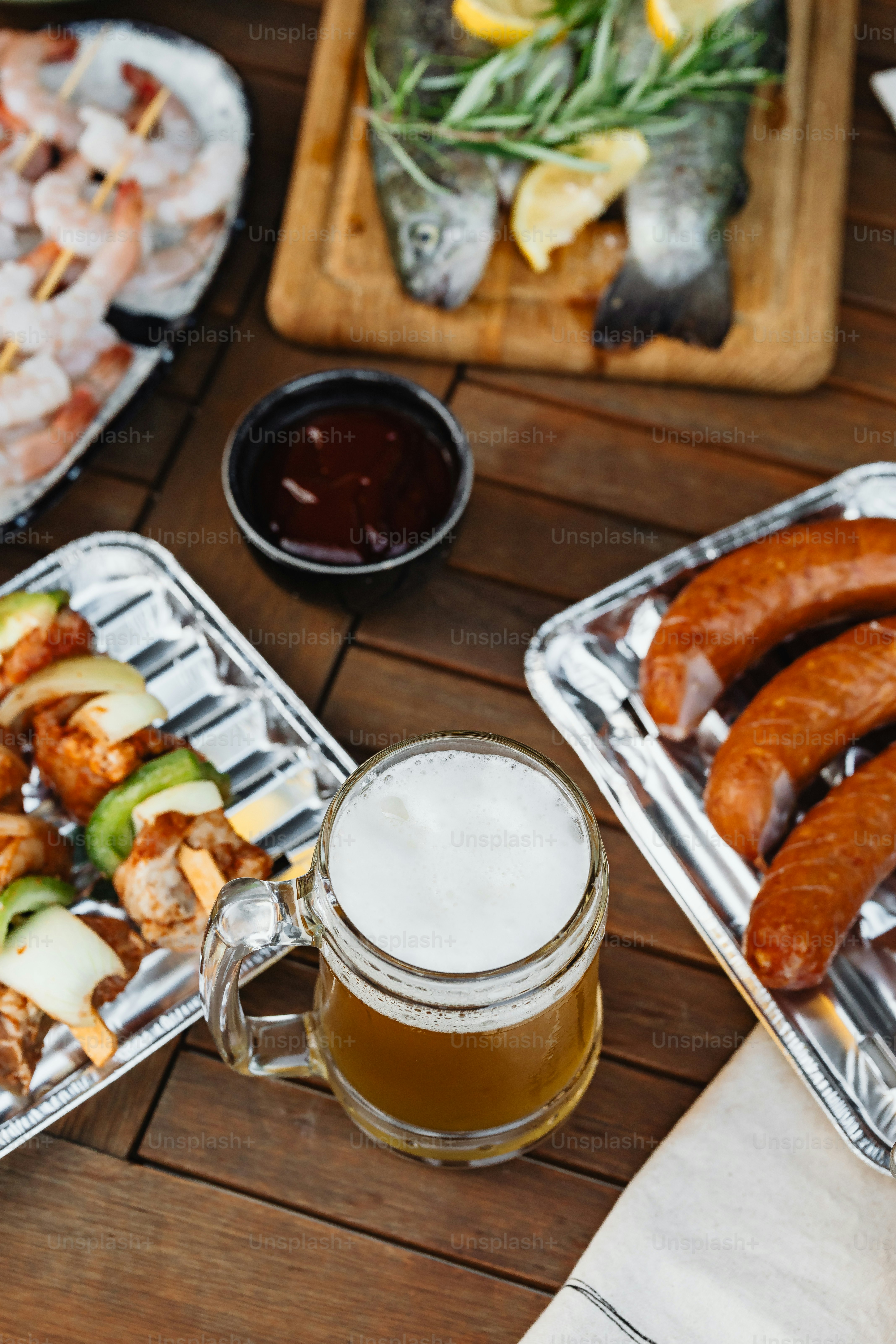 A wooden table topped with trays of food and drinks photo – Summer food ...
