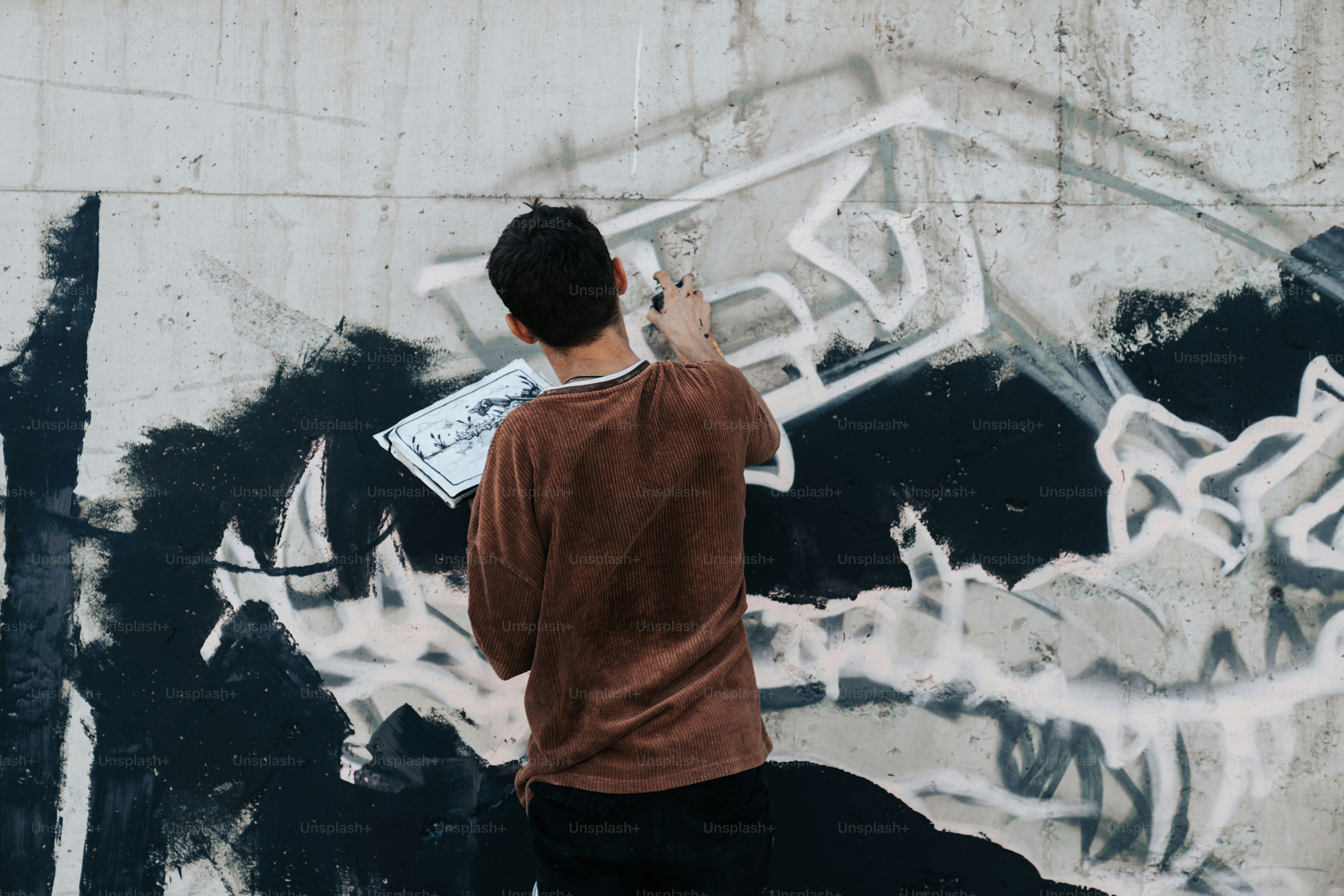 Un homme debout devant un mur avec des graffitis dessus photo – Mural ...