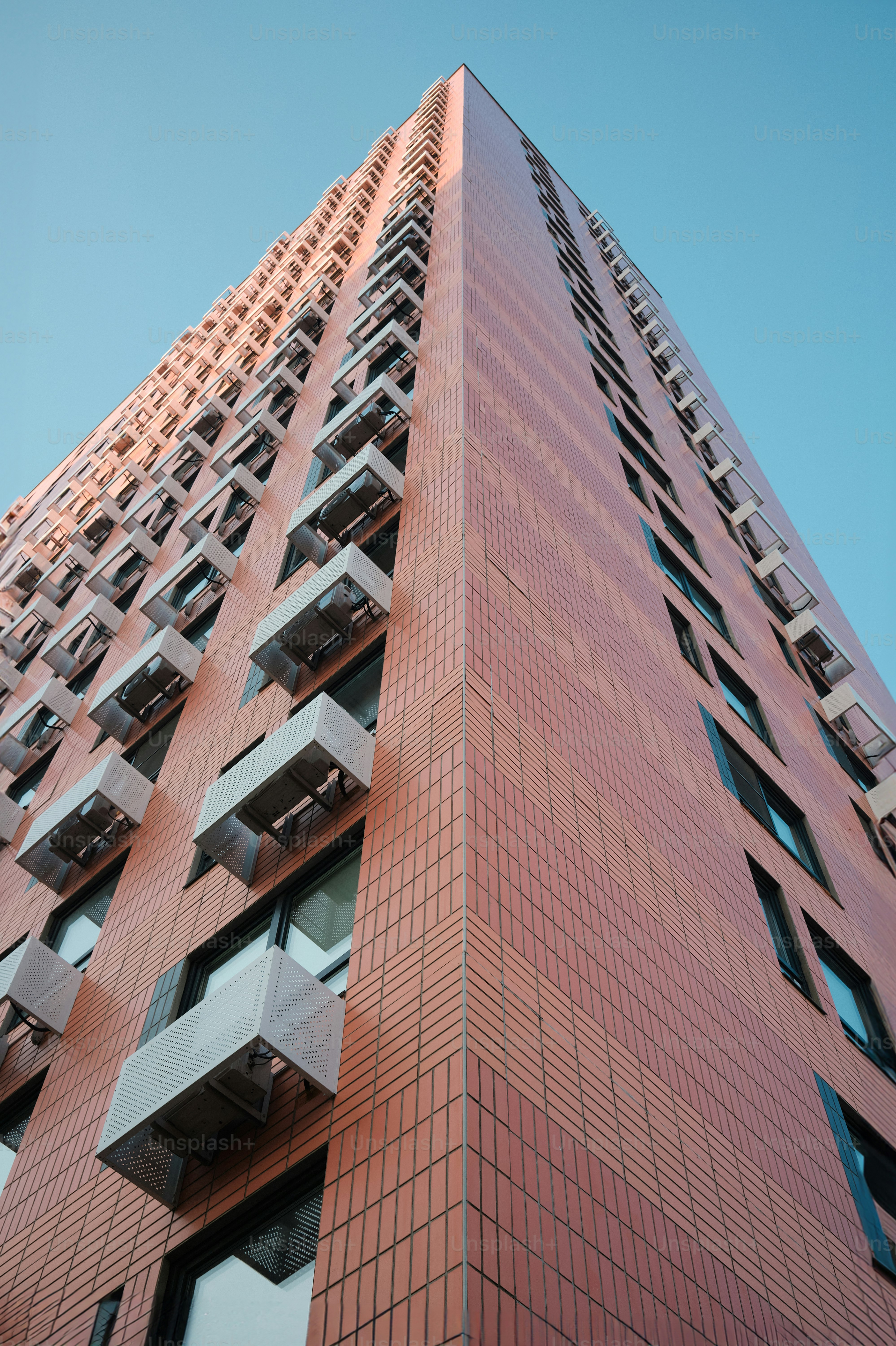 A tall red brick building with balconies and balconies photo – Colorful ...