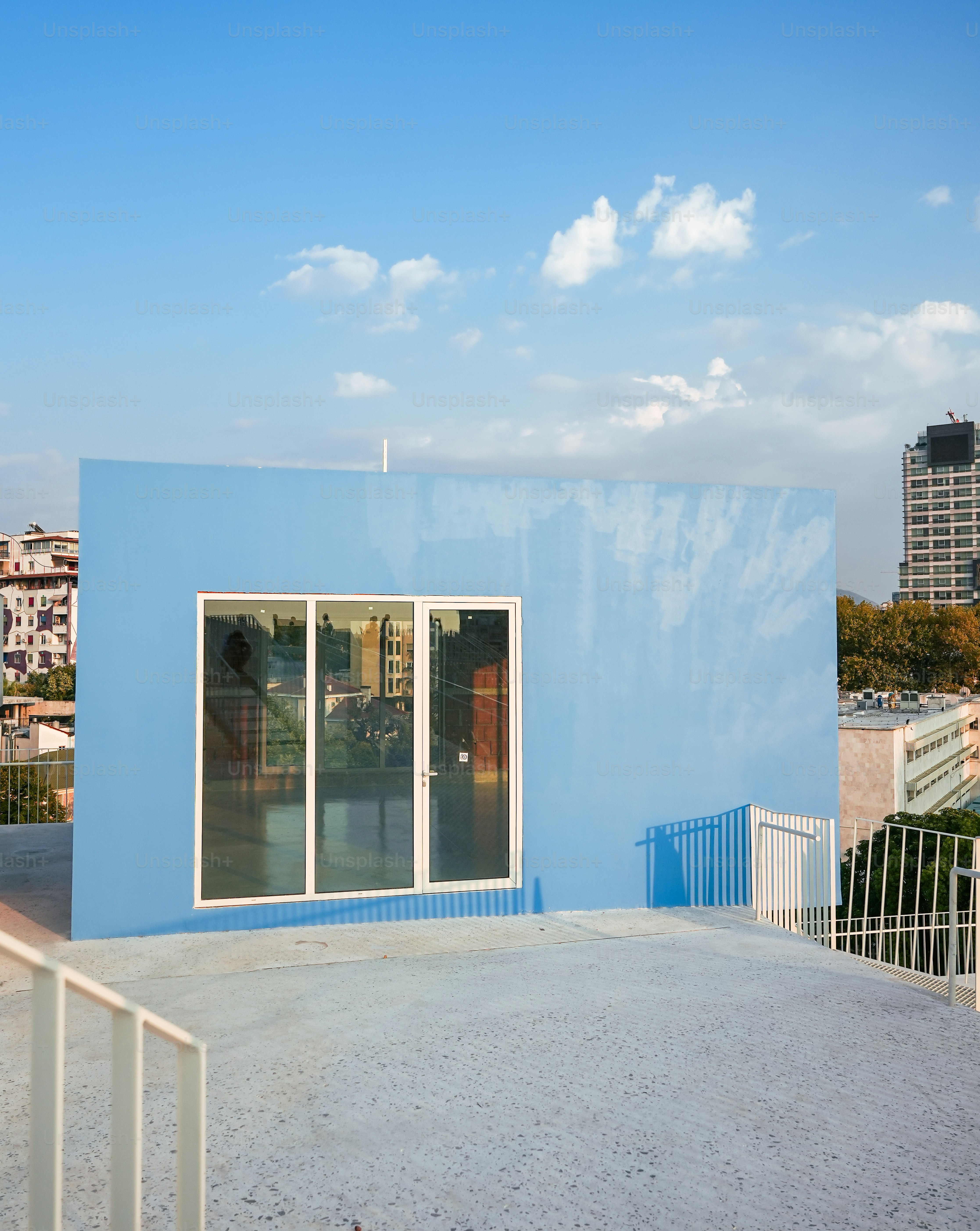 A blue building with a glass door and railing photo – Colorful ...