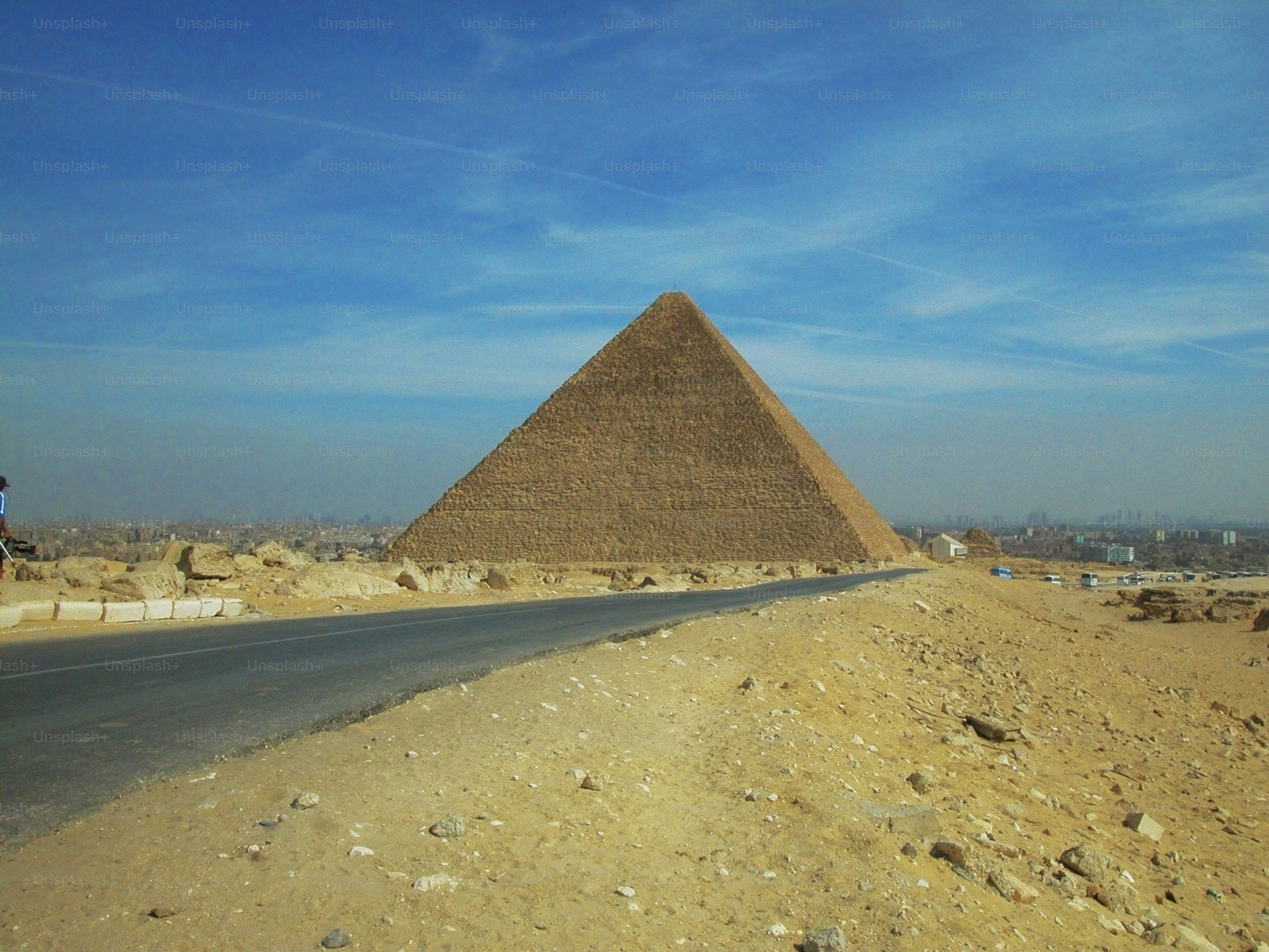 A man riding a bike down a road next to a large pyramid photo – Middle ...