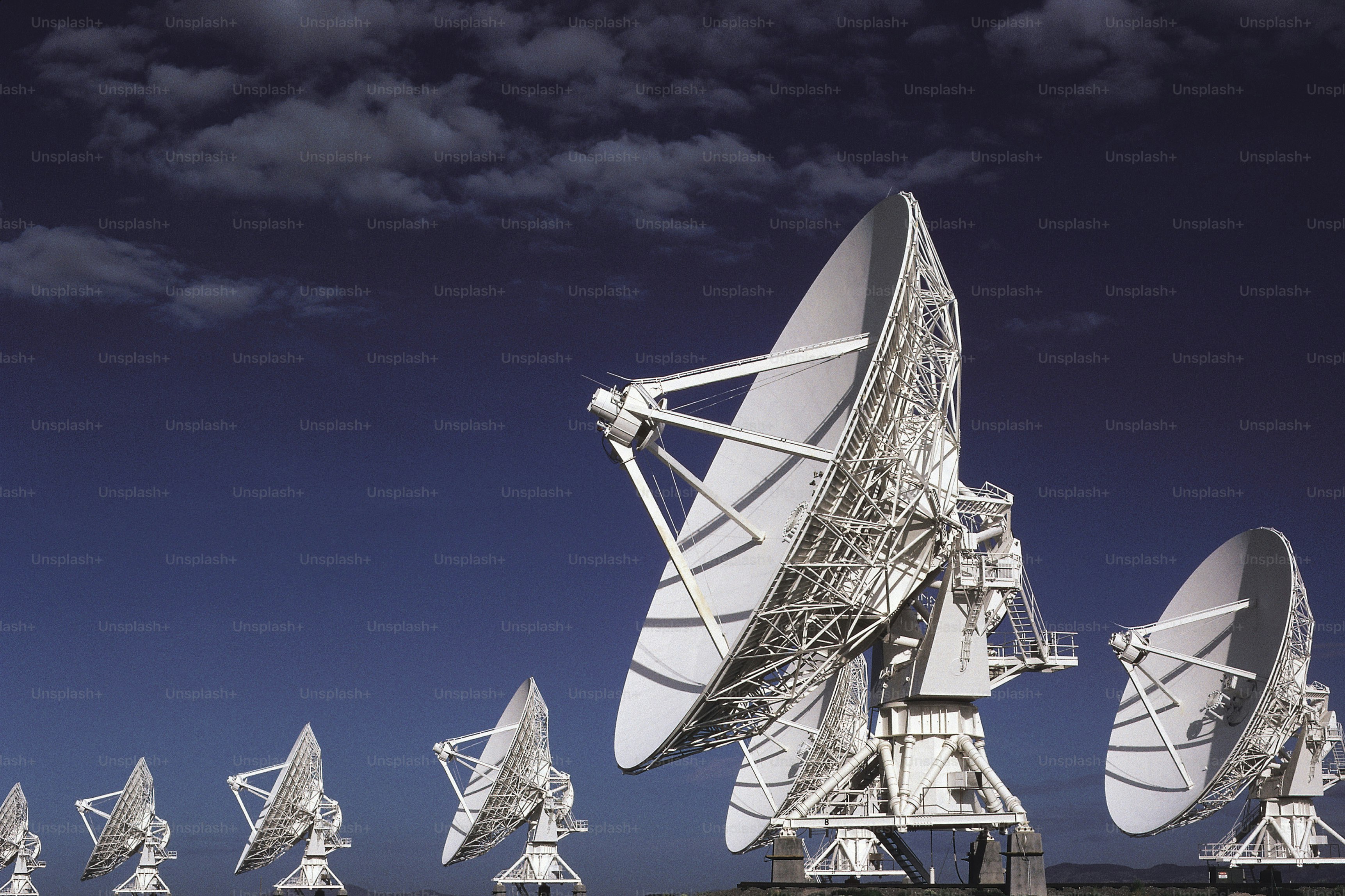 A large array of satellite dishes sitting on top of a field photo ...