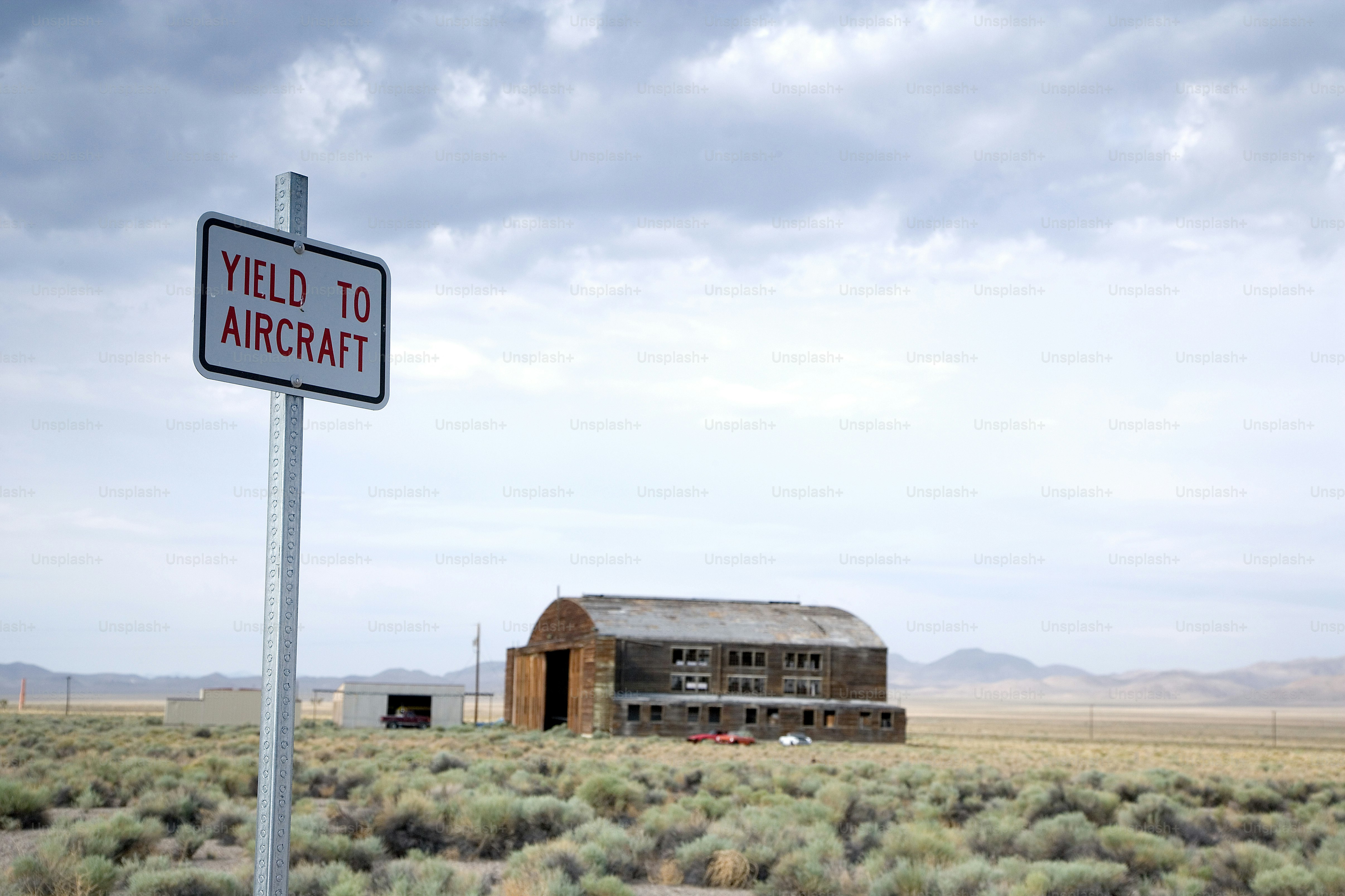 A field with a building and a sign that says yield to aircraft photo ...