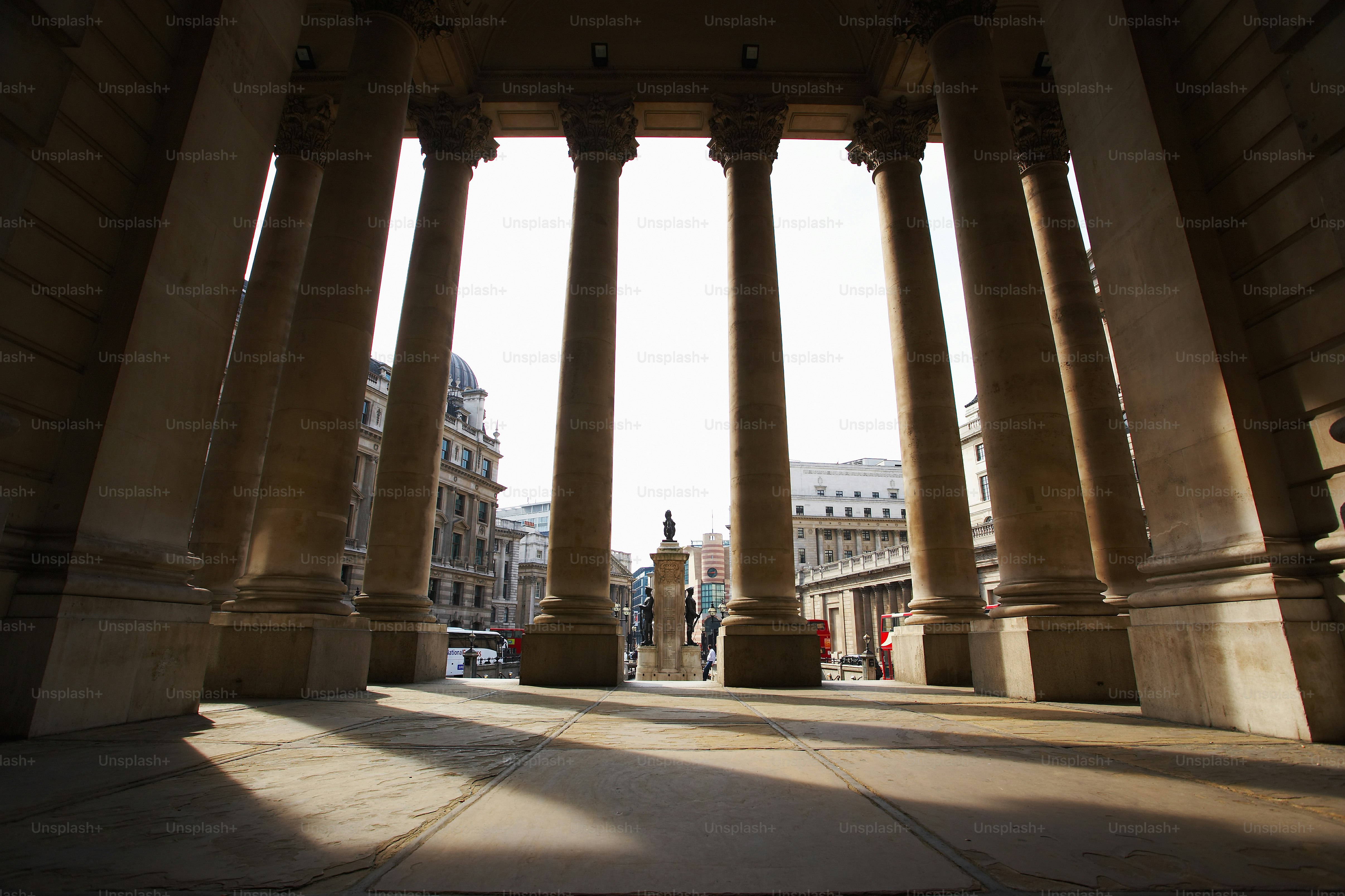The sun is shining through the pillars of a building photo – London ...