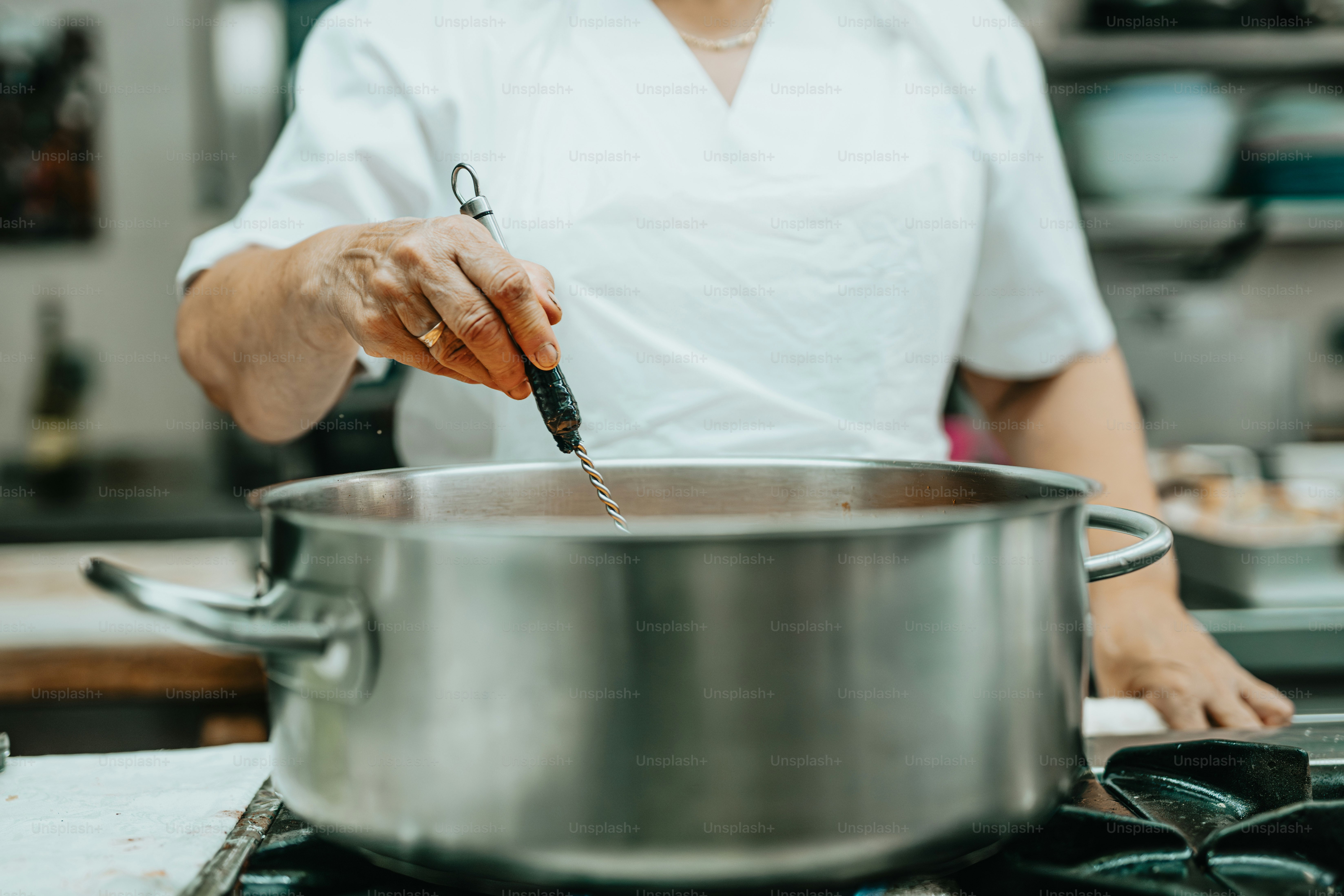 A person in a kitchen stirring something in a pot photo – Cooking Image ...
