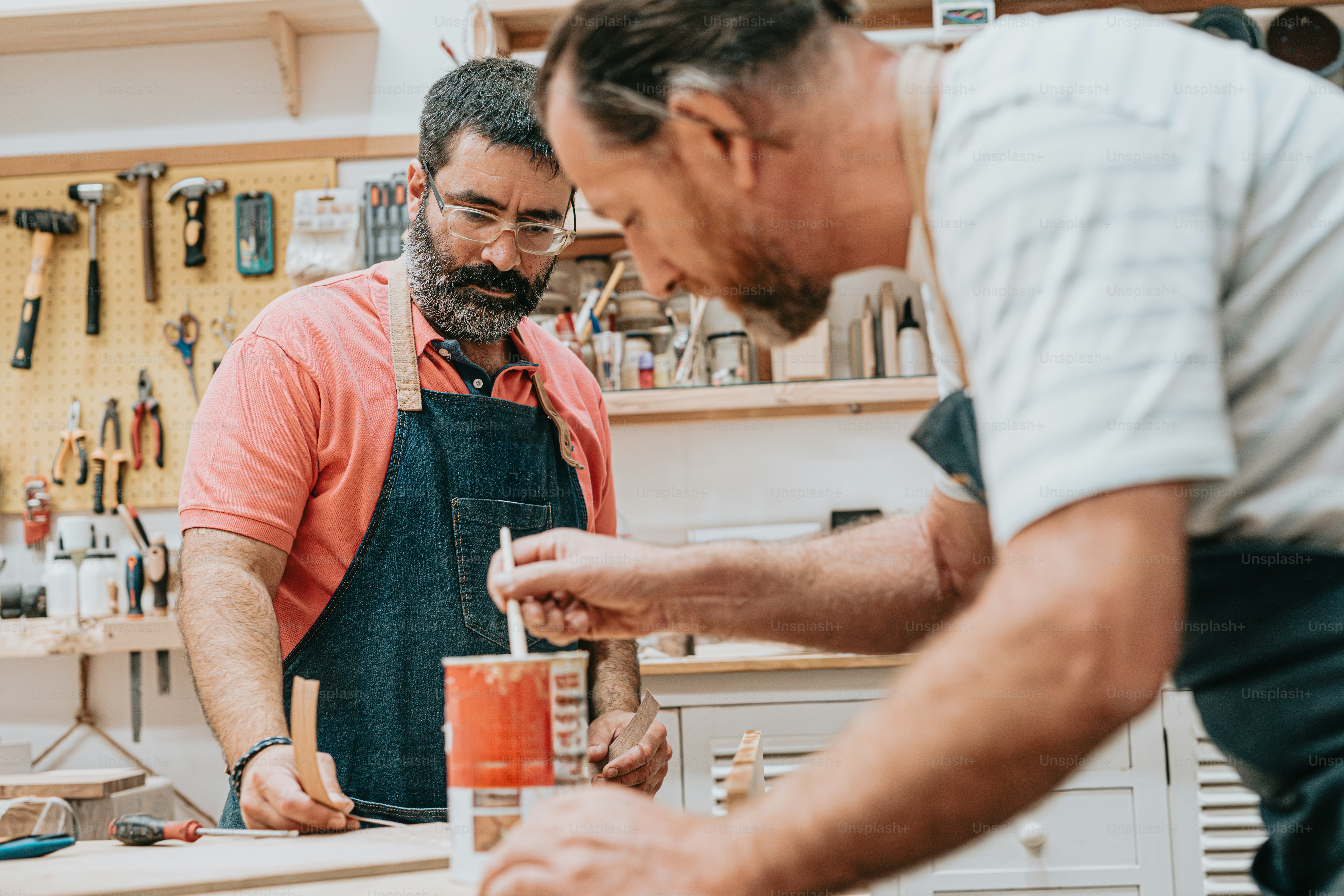 Two men in a workshop working on a piece of wood photo – People Image ...