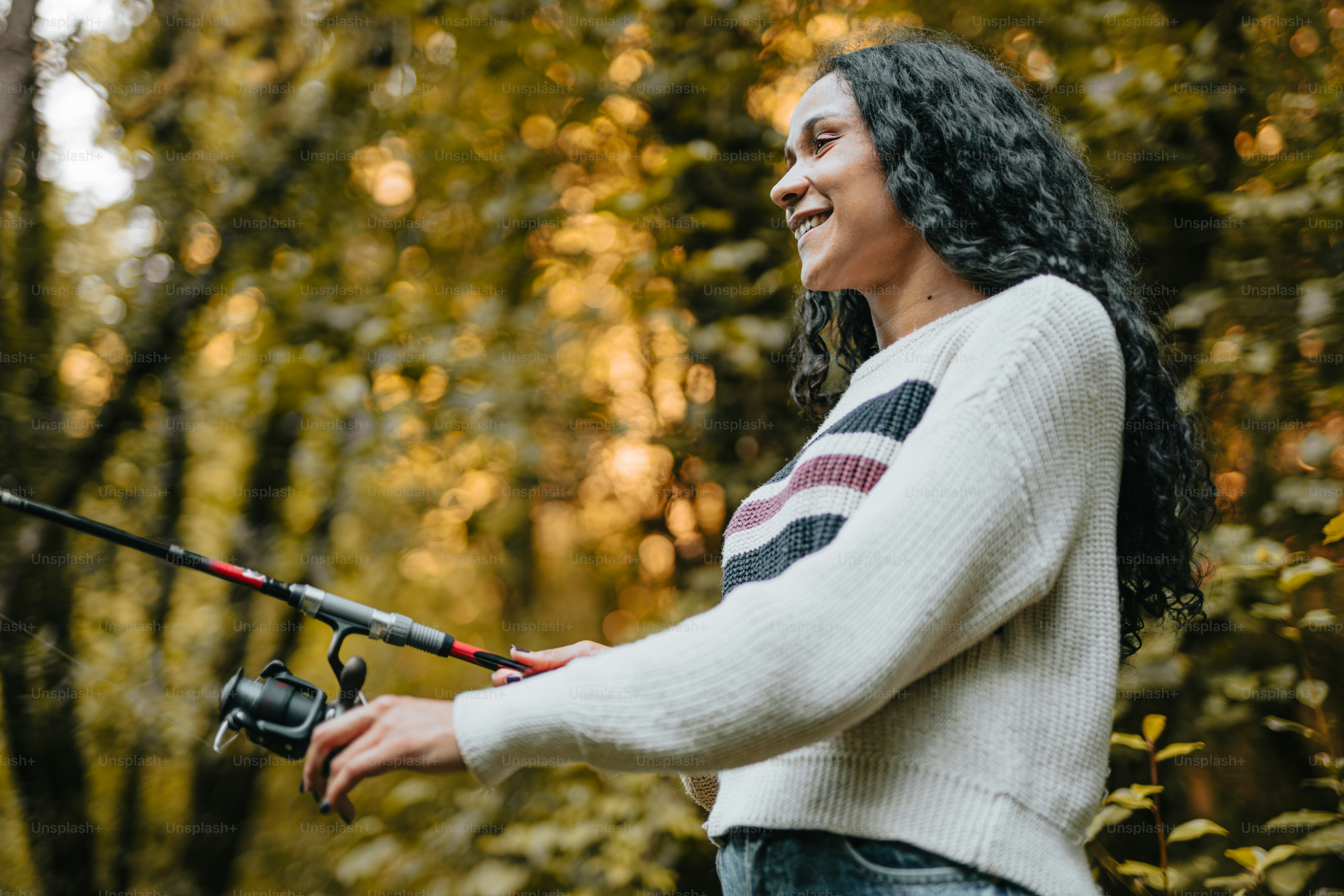 A woman smiles while holding a fishing rod photo – Fishing Image on ...