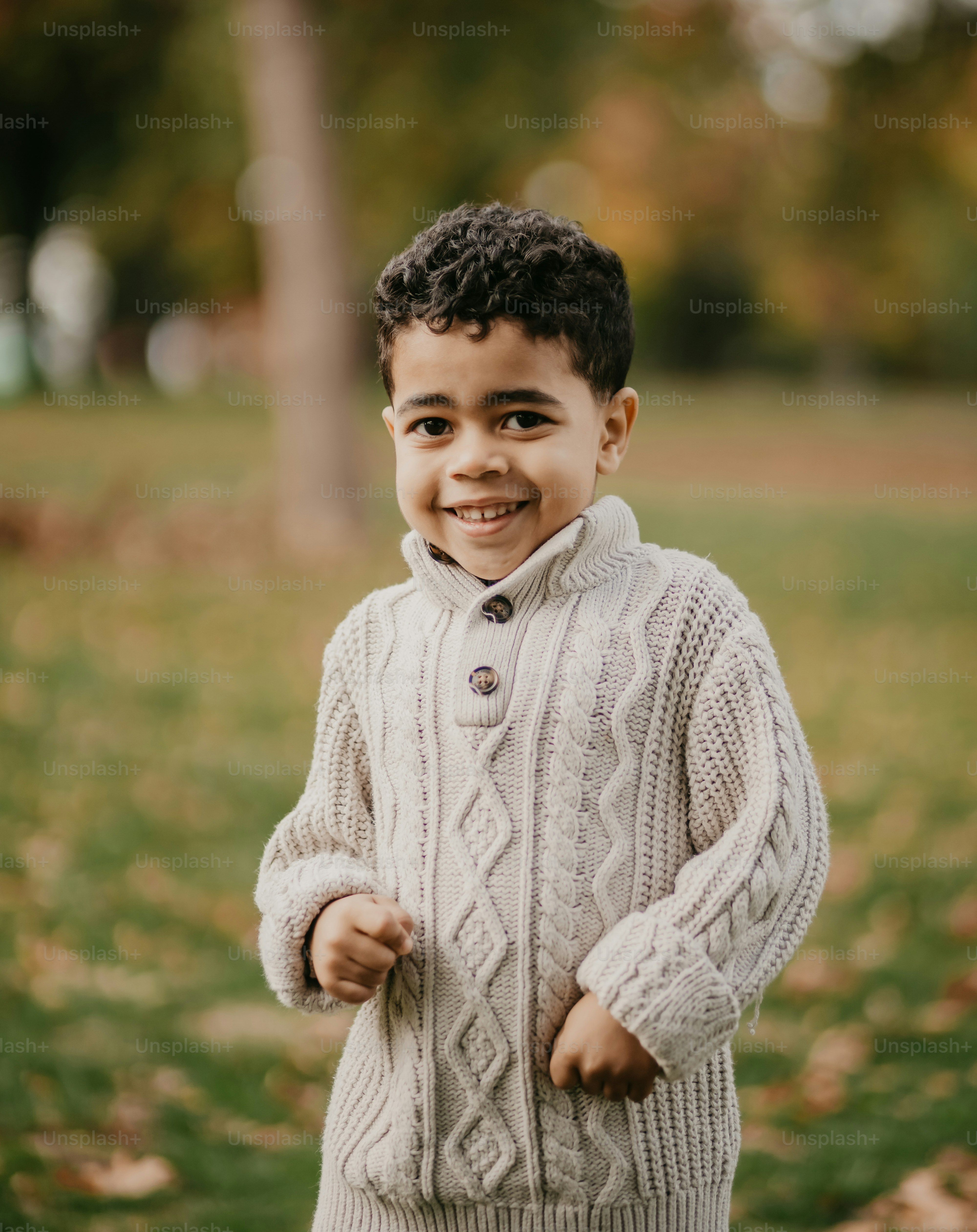 A young boy smiles while standing in a field photo – Young boy Image on ...