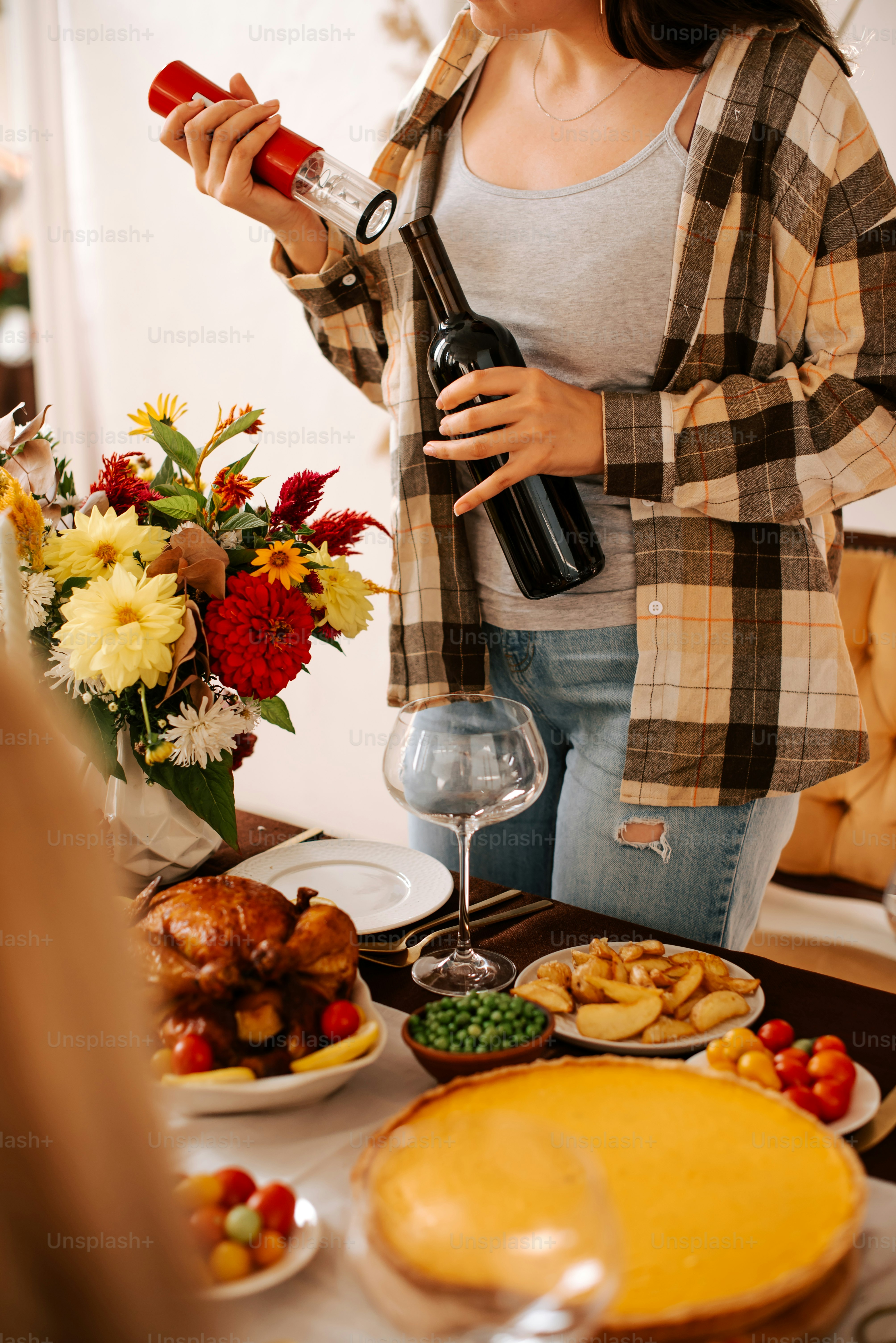 Une femme versant un verre de vin devant une table pleine de nourriture ...