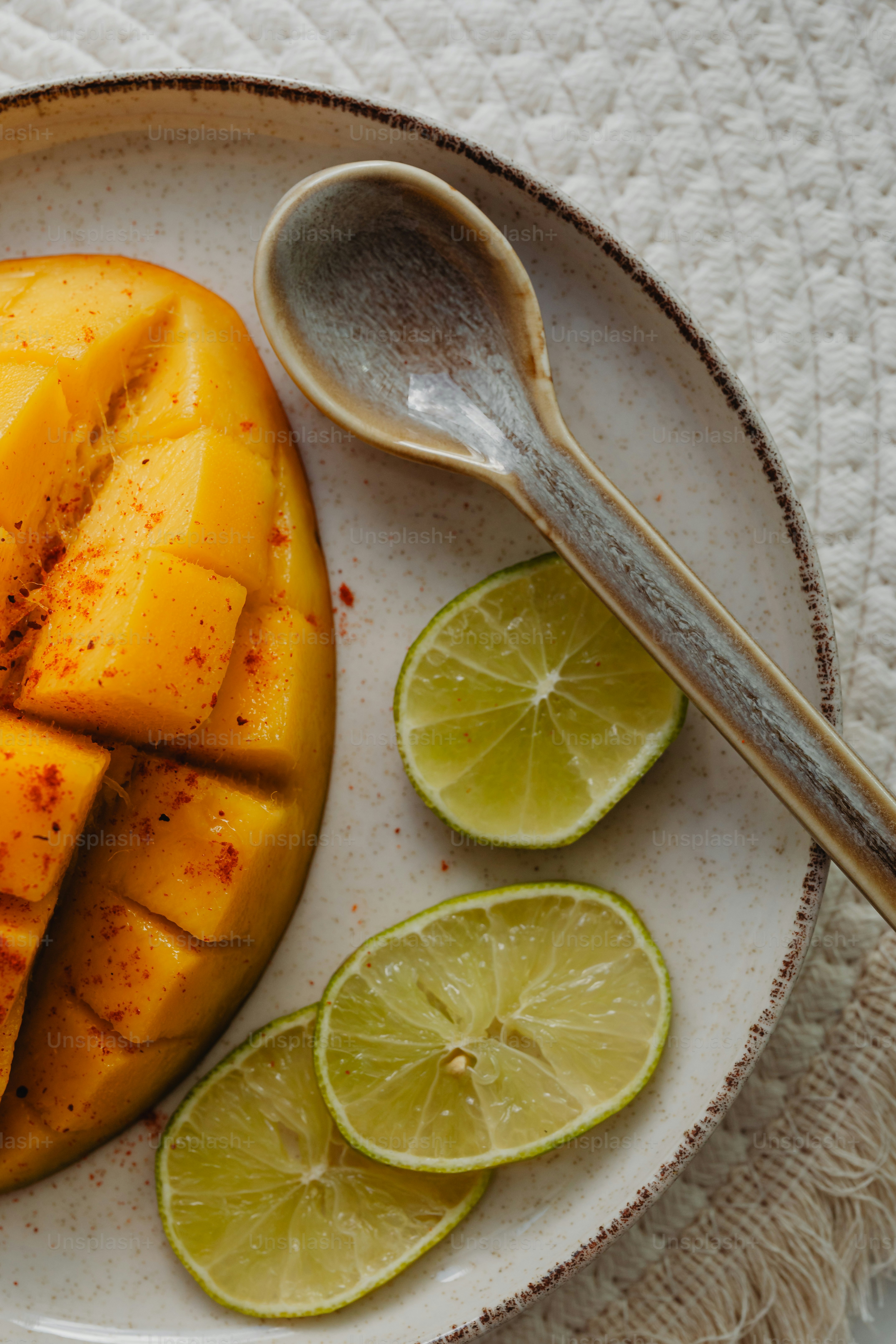 A white plate topped with sliced mangoes and limes photo – Mango Image ...