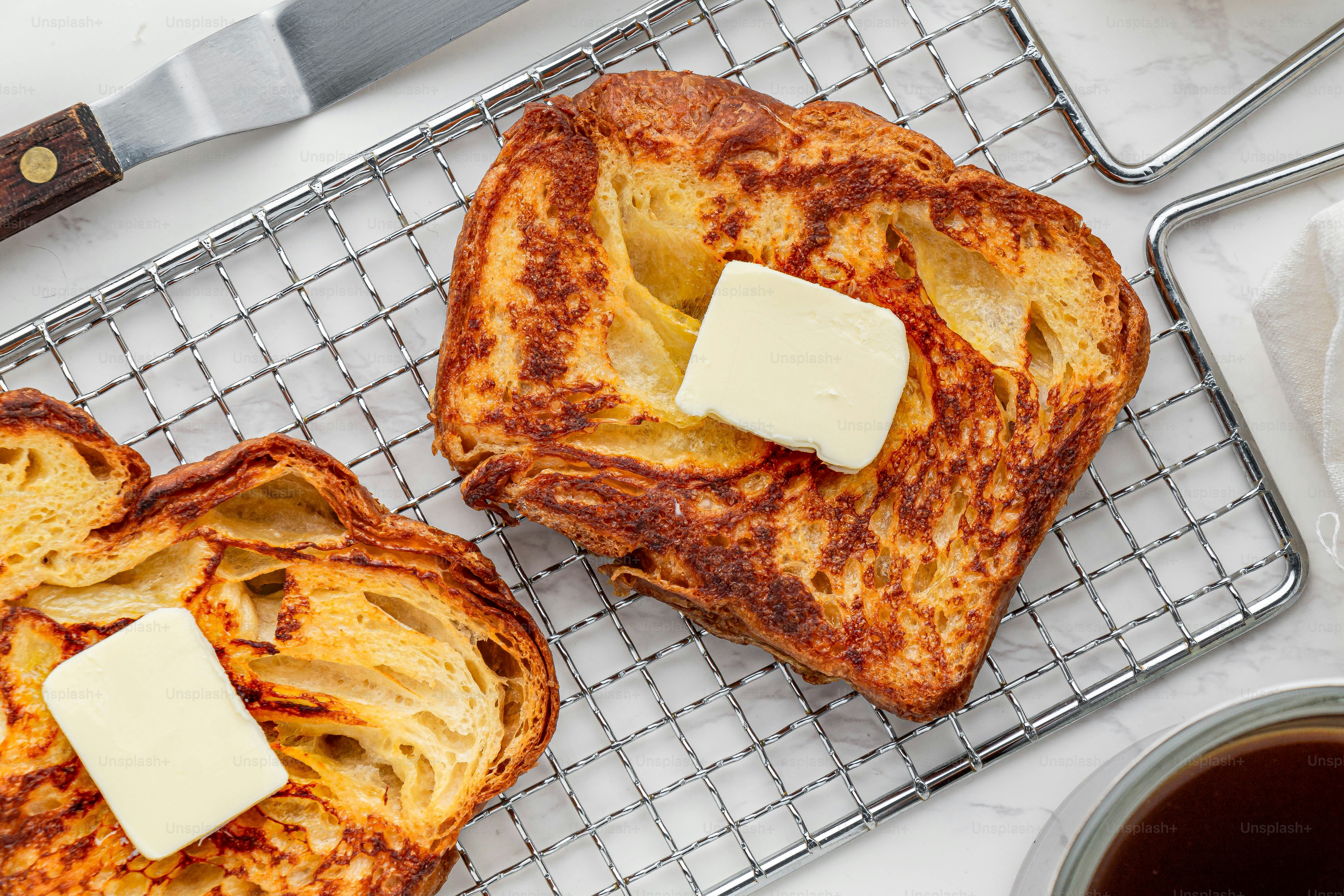 Two pieces of french toast with butter on a cooling rack photo – French ...