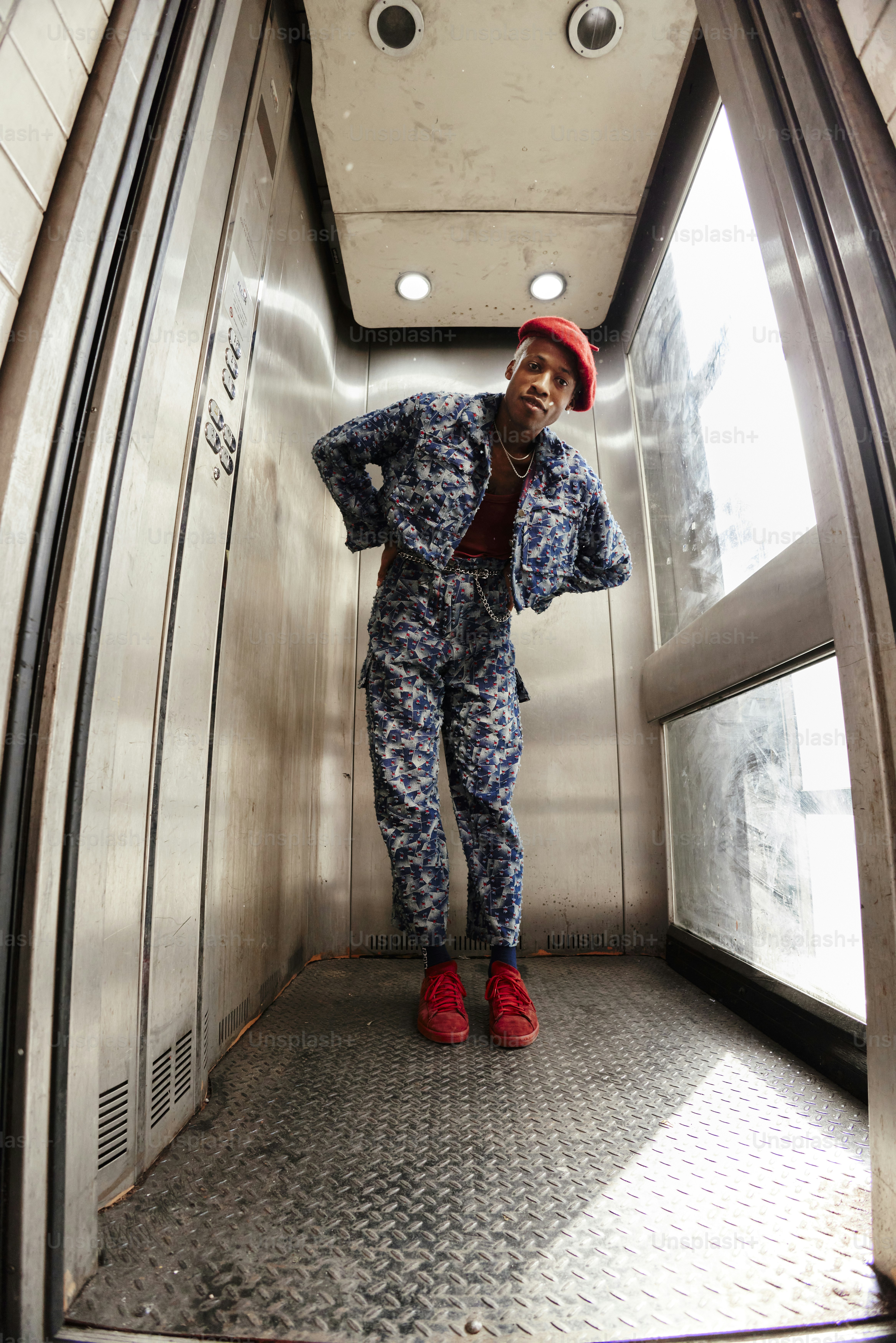 A man in a red hat and blue jumpsuit standing in an elevator photo ...