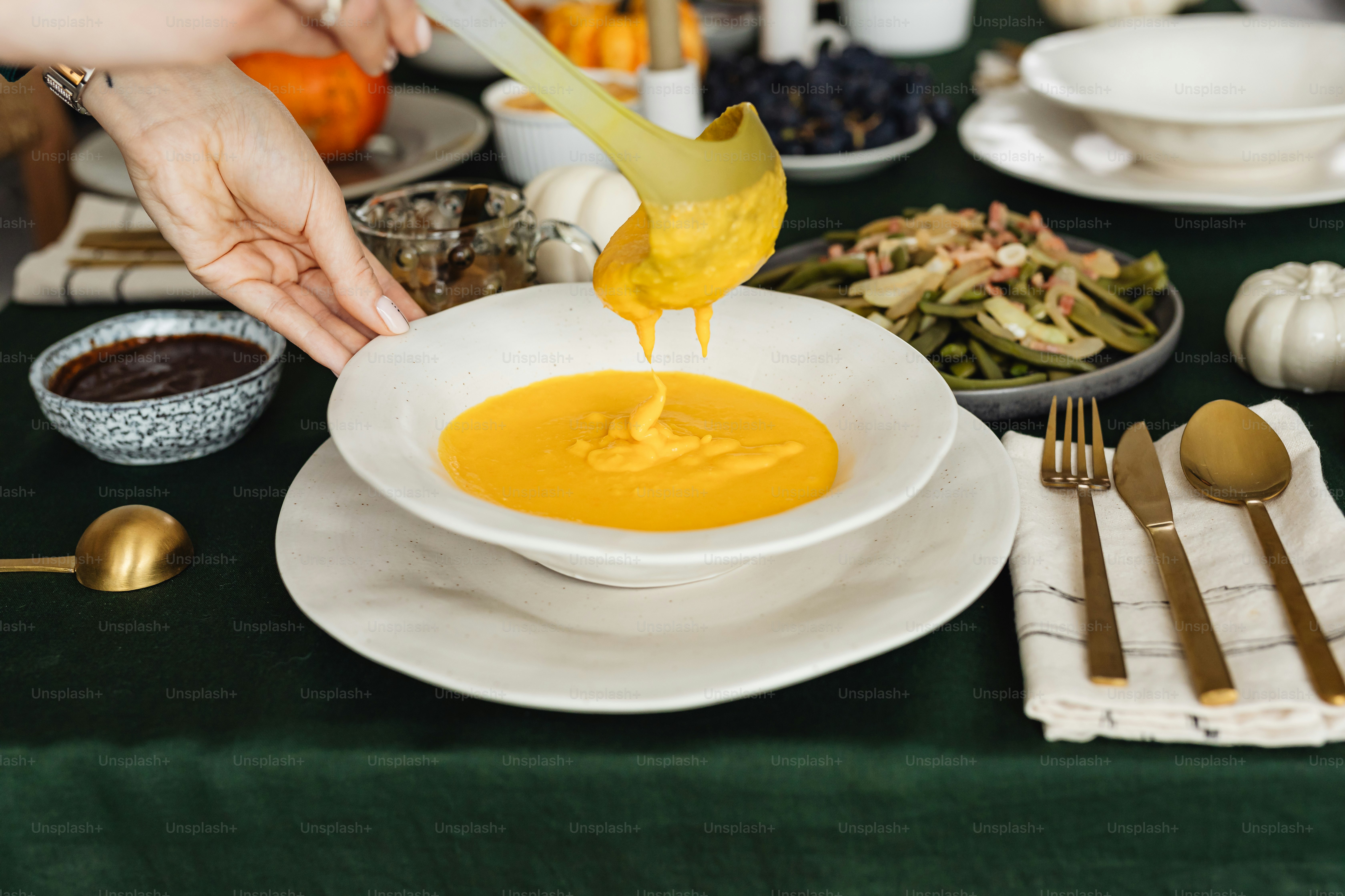 A person pouring a spoon into a bowl of soup photo – Thanksgiving table ...
