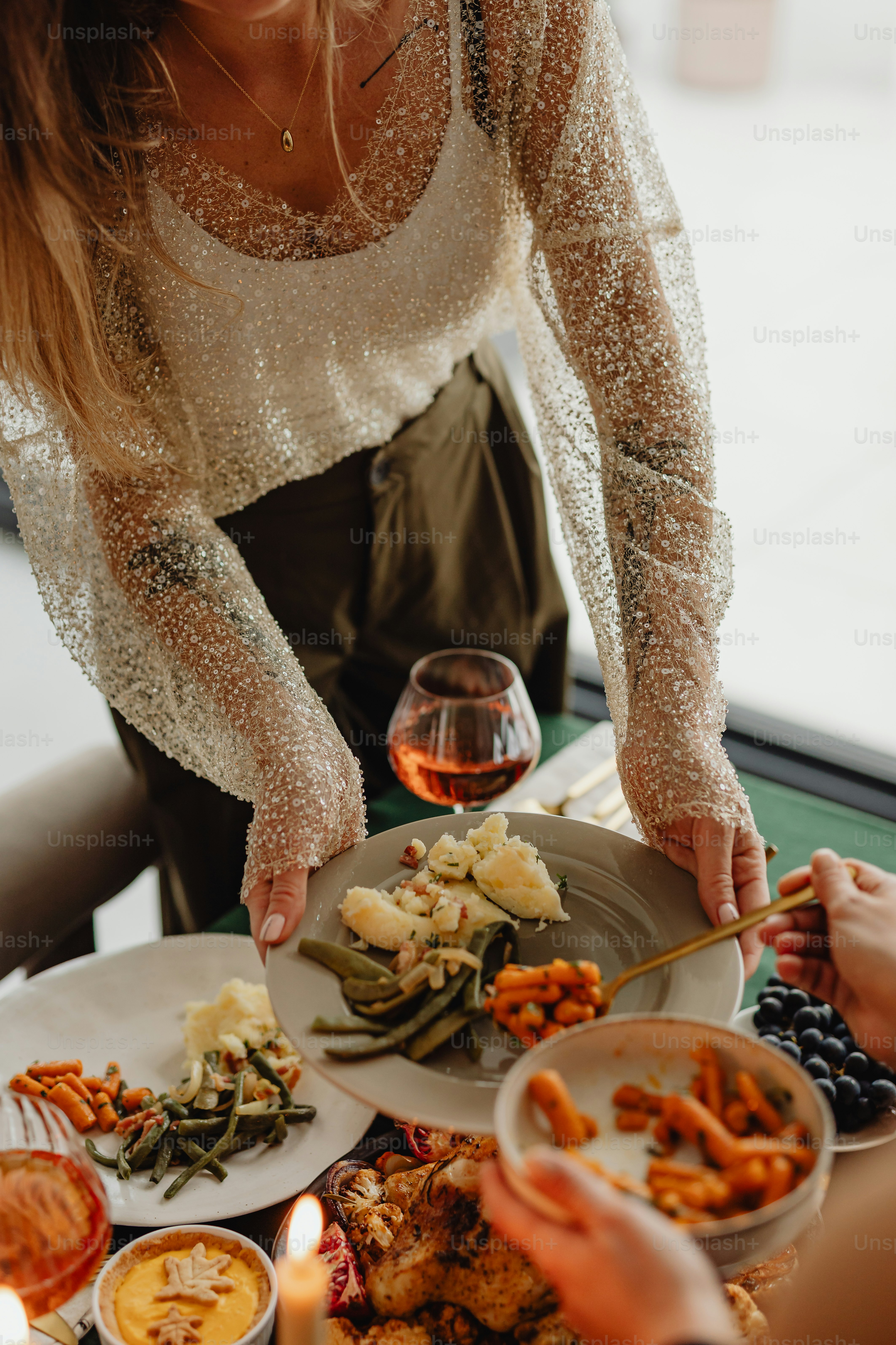 A woman standing over a table filled with plates of food photo – Family ...