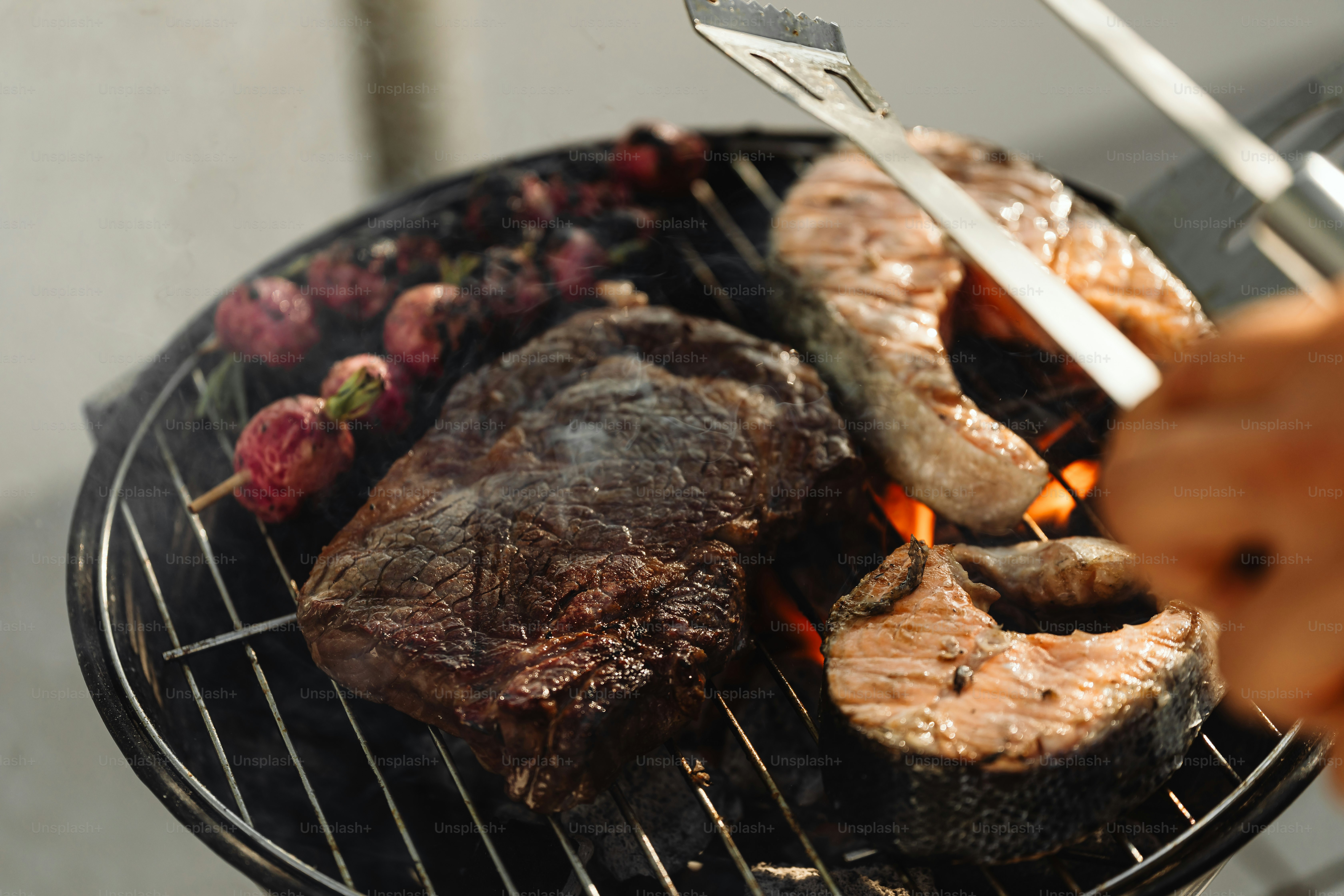 Una persona asando filetes y verduras en una parrilla foto – Imagen de ...